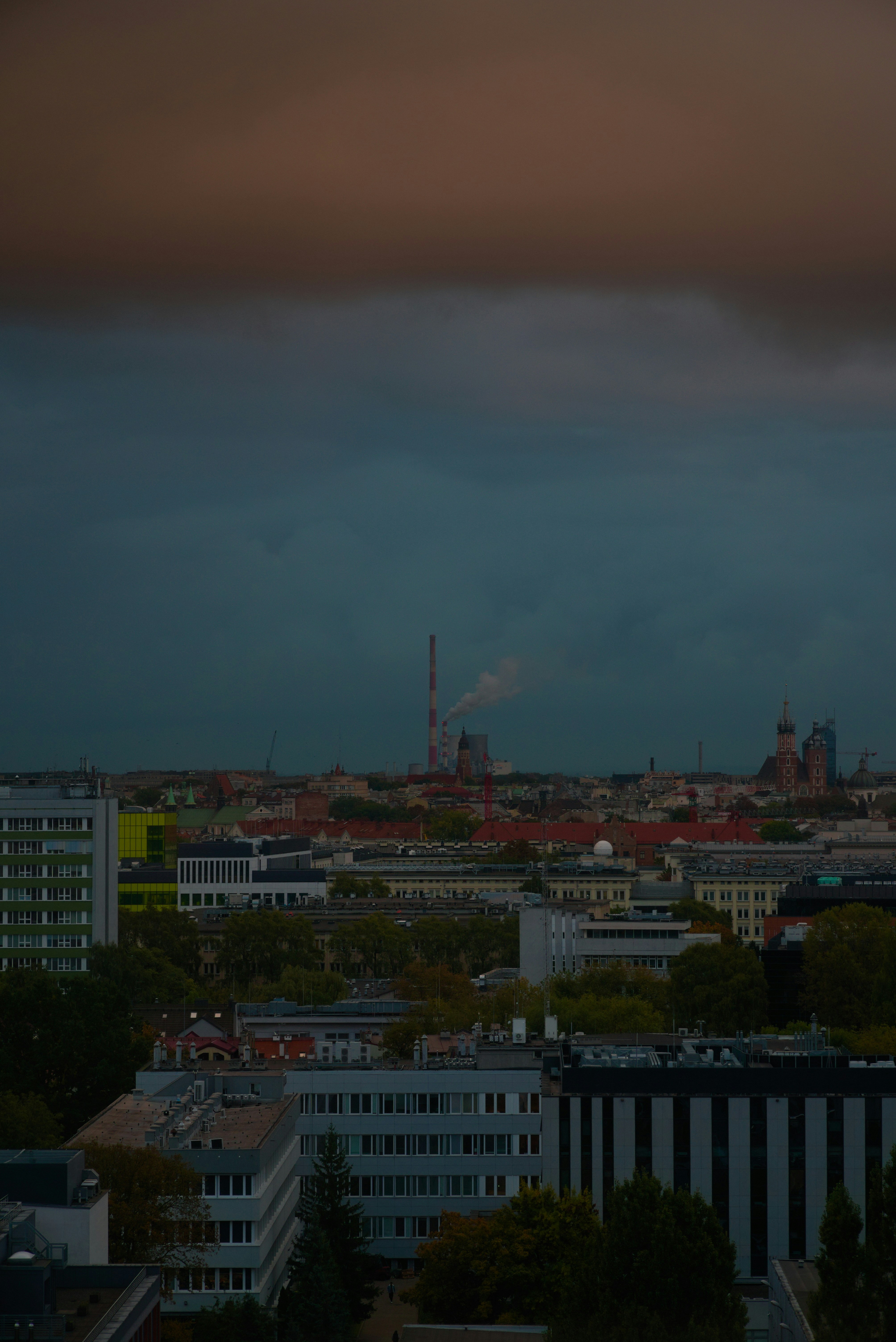 City skyline with smokestacks under a stormy sky