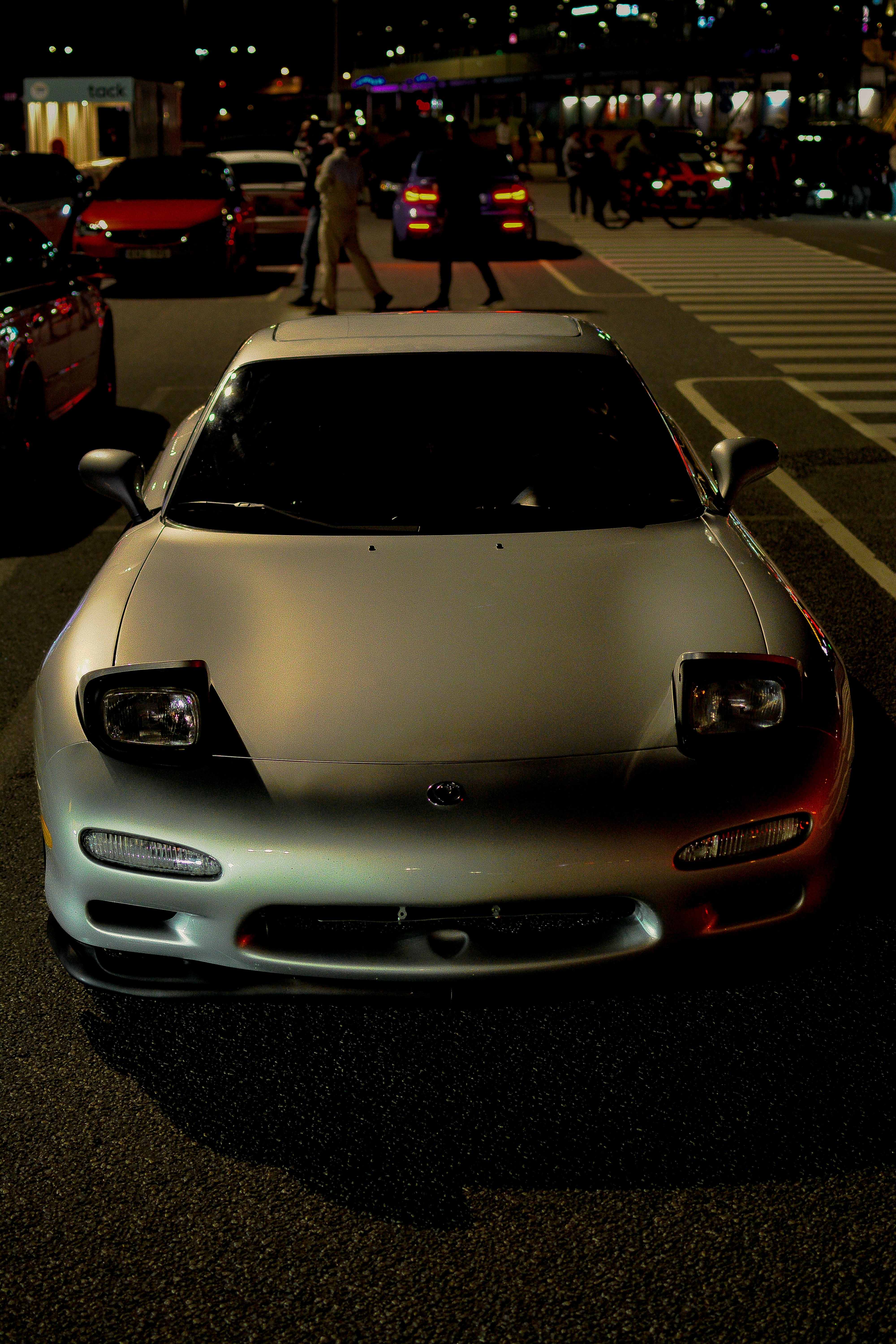 Silver sports car parked on a city street at night