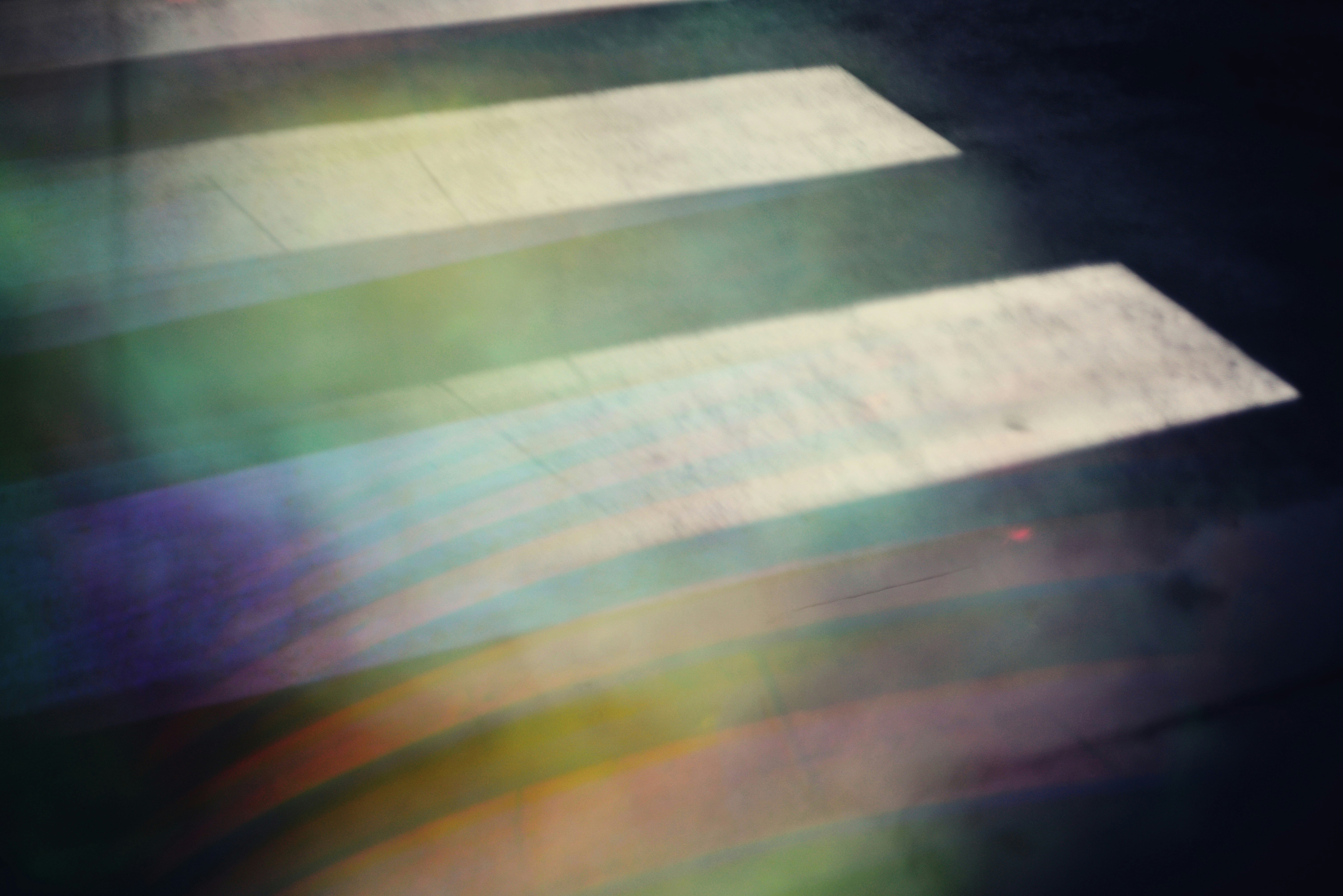 Crosswalk stripes with colorful light streaks.