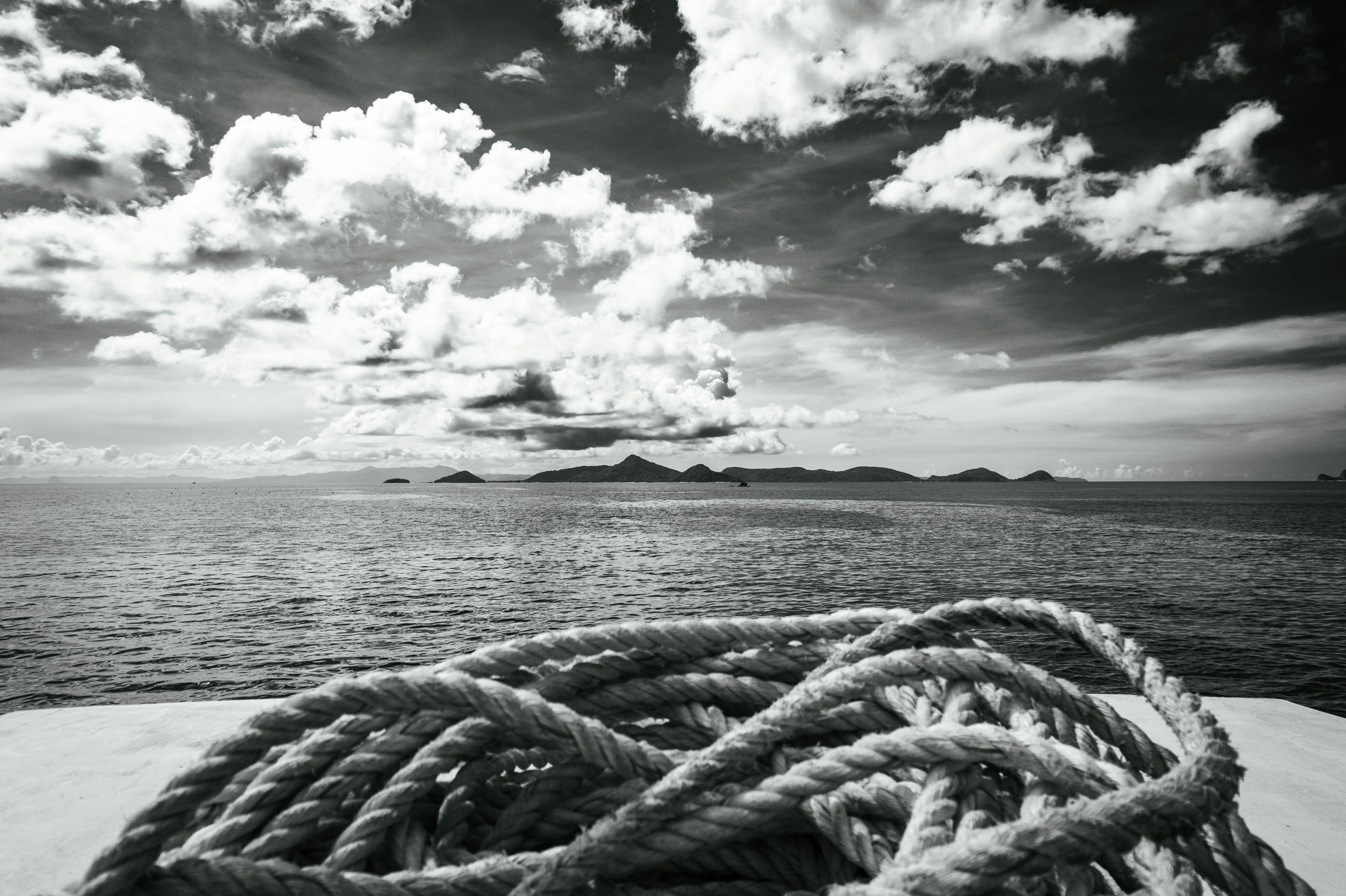 Coiled rope on boat deck with ocean and islands