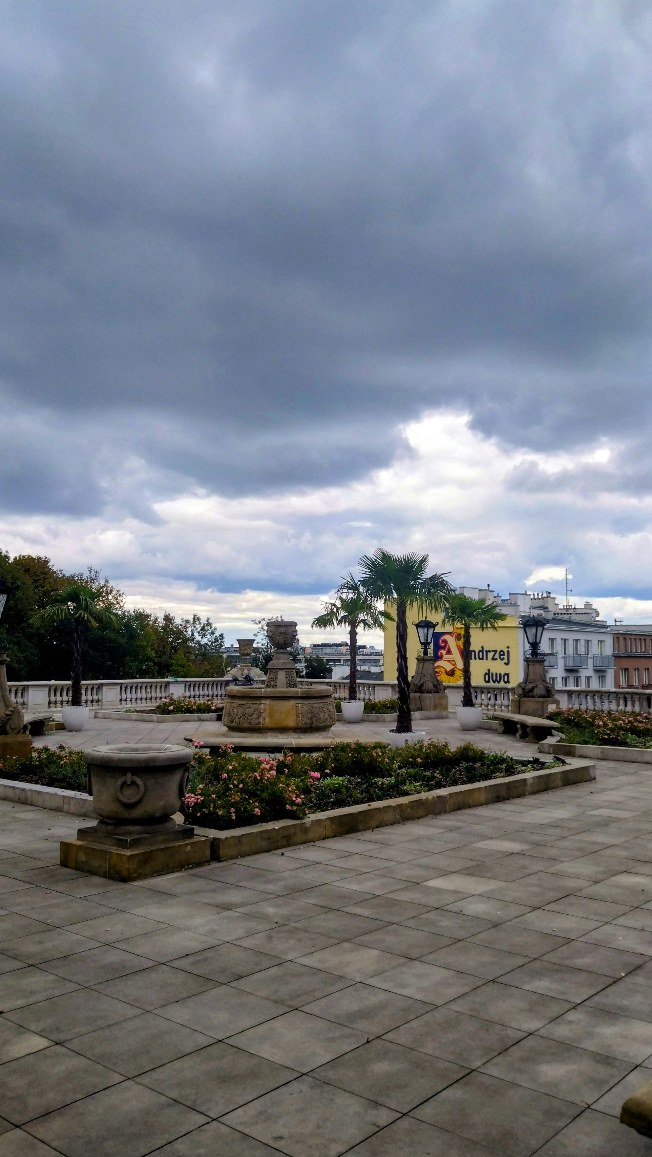 Terraced garden with fountain and palm trees under cloudy sky