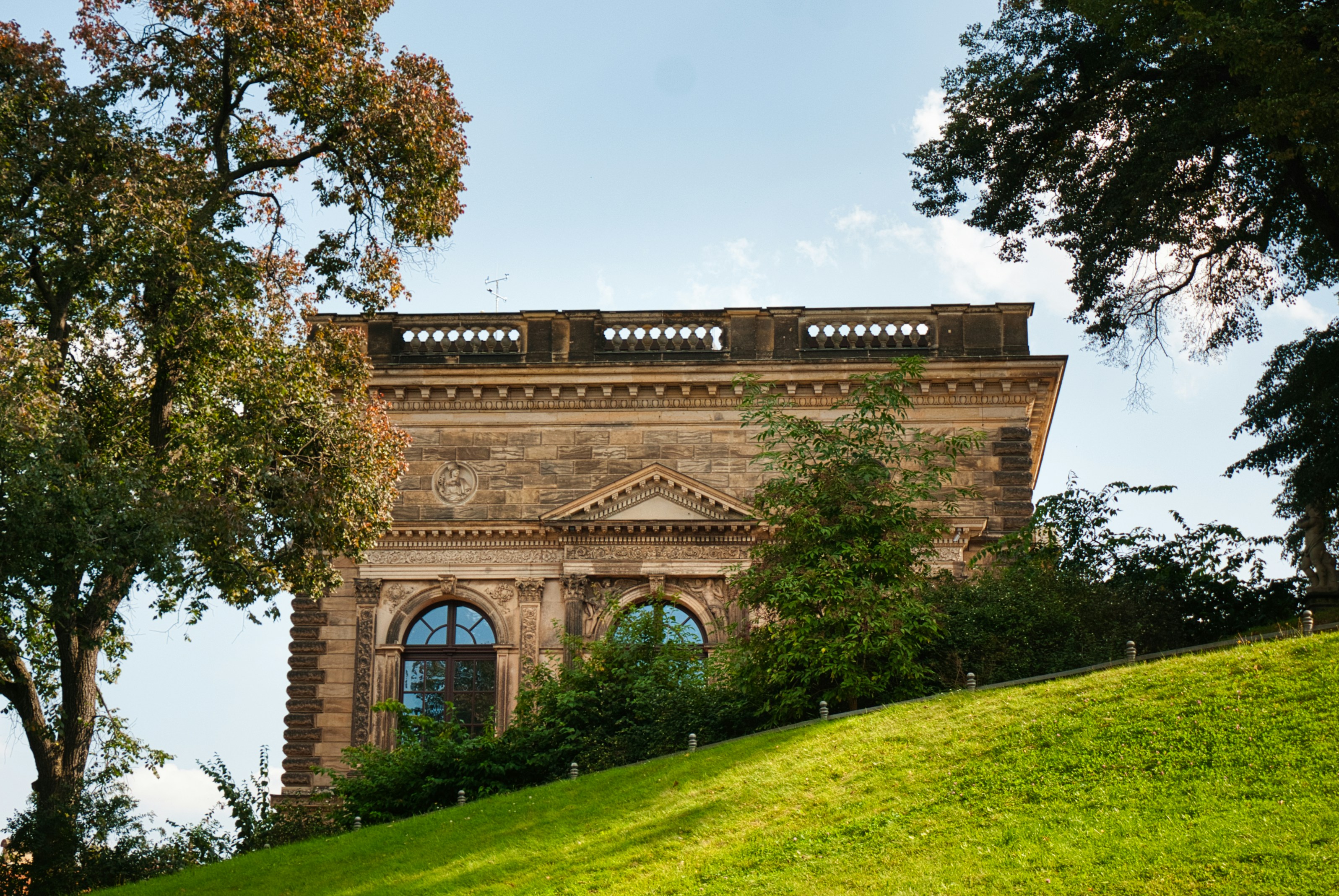 Beaux-Arts on the Hill: Sunlit Facade Rising Above the Green Slope
