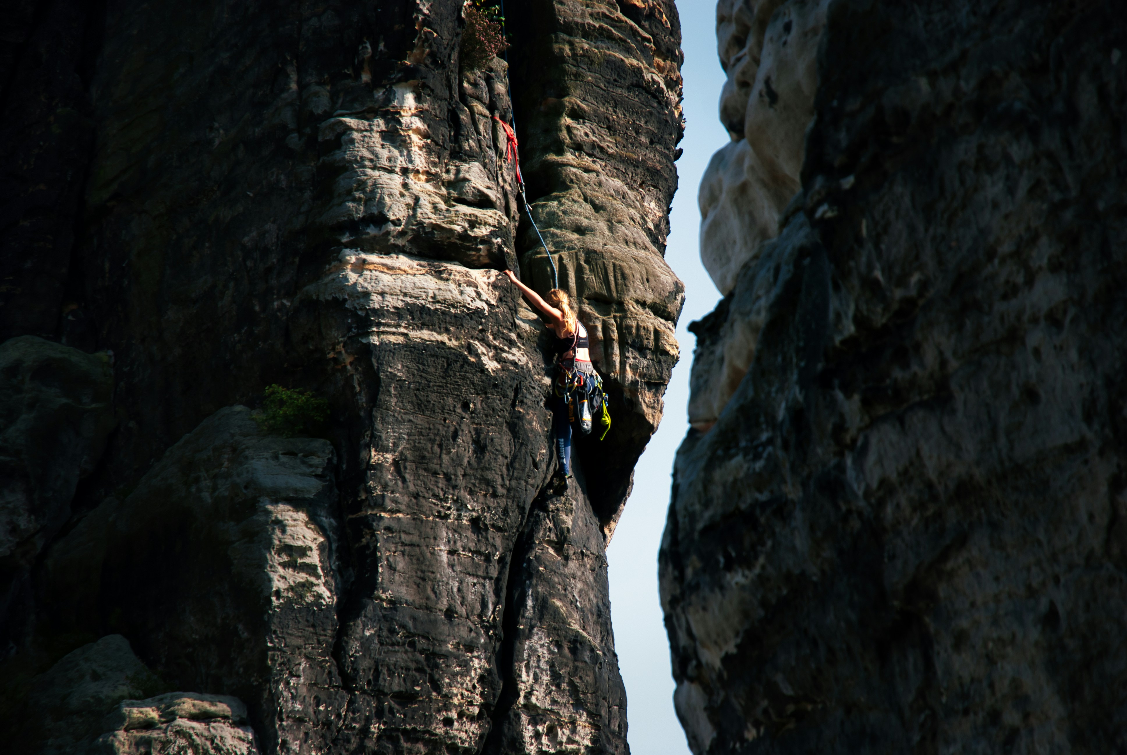 A rock climber ascends a steep cliff face.