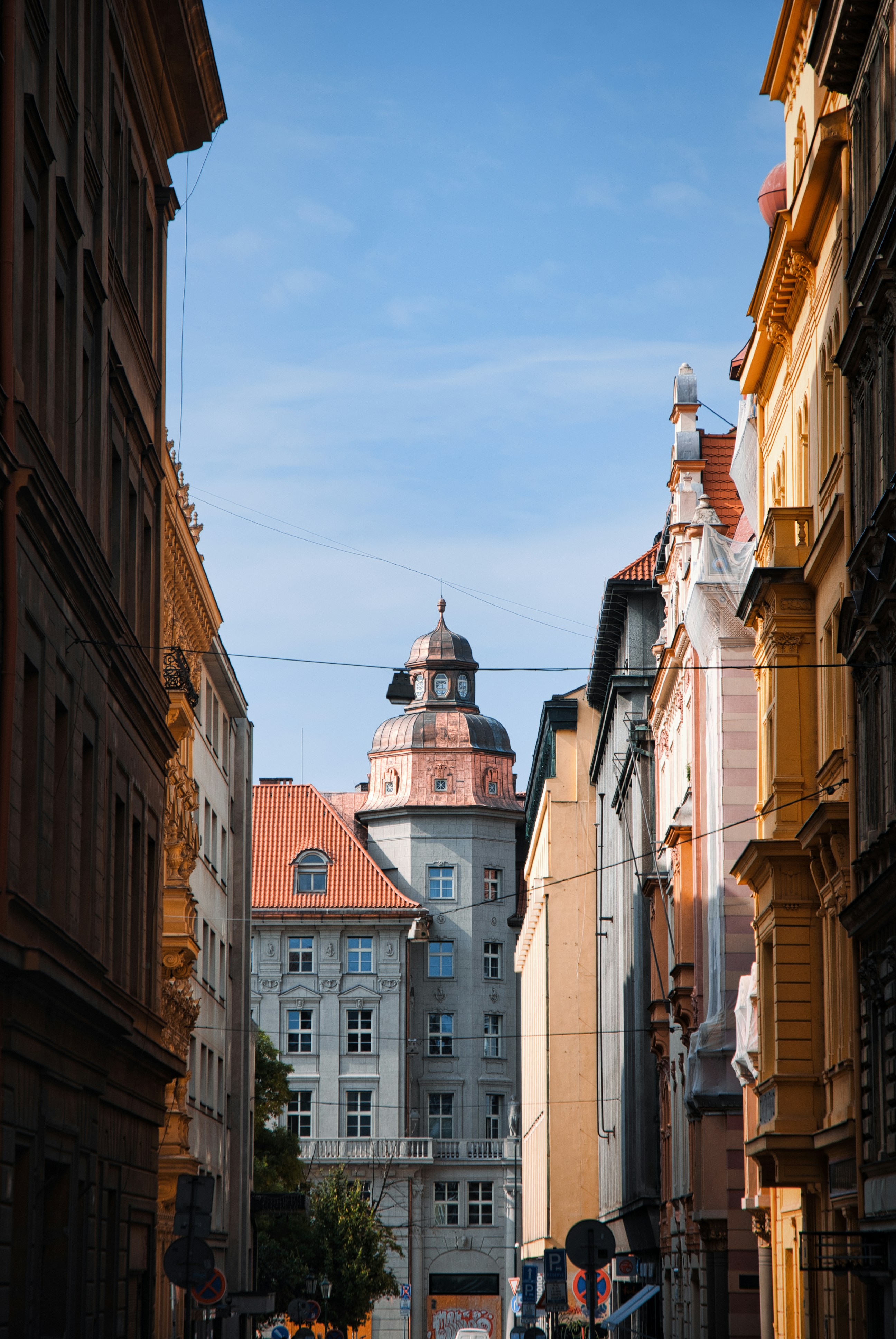 Historic building framed by colorful facades of narrow street, showcasing architectural diversity under a clear sky.