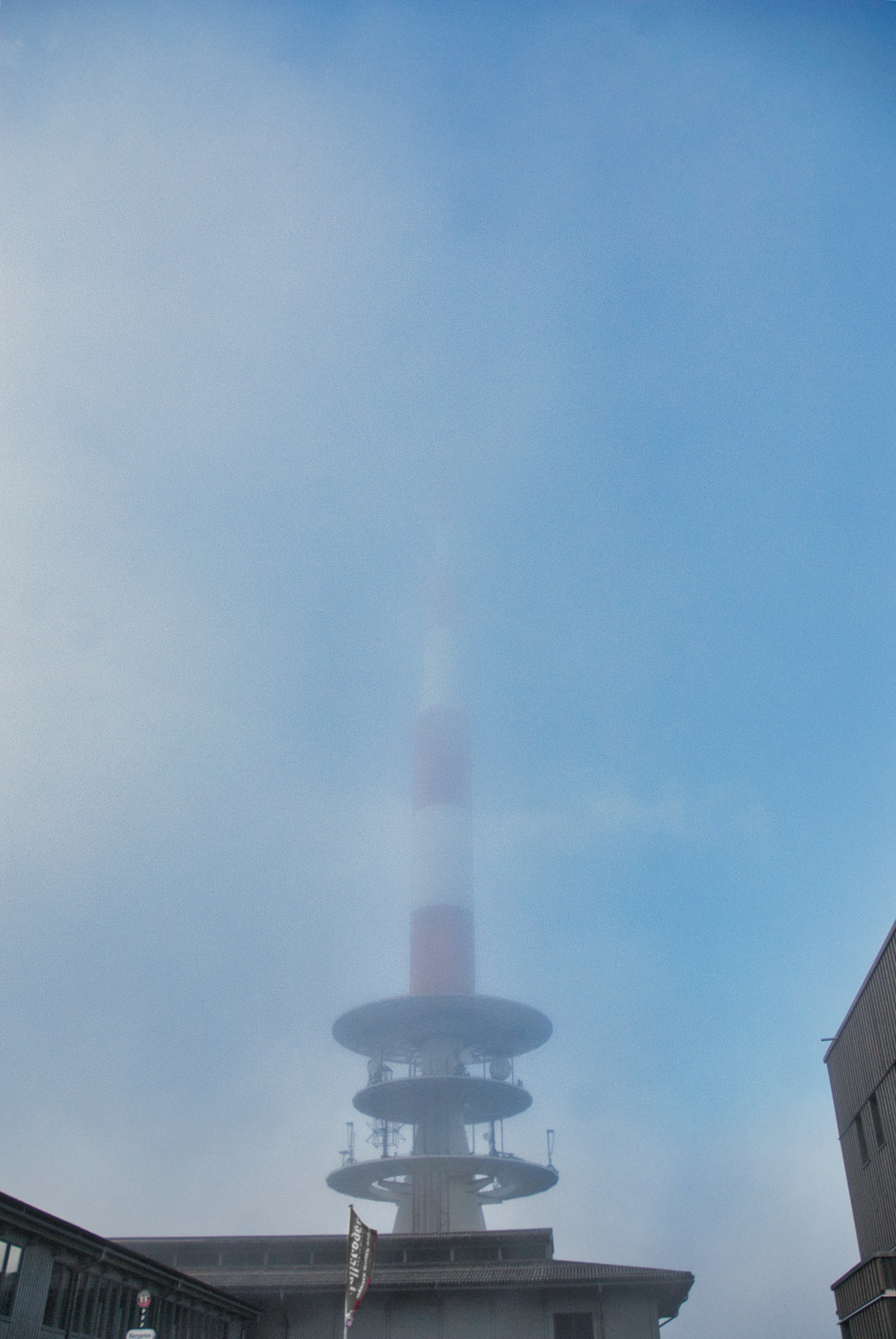 Tower partially obscured by fog against a blue sky.