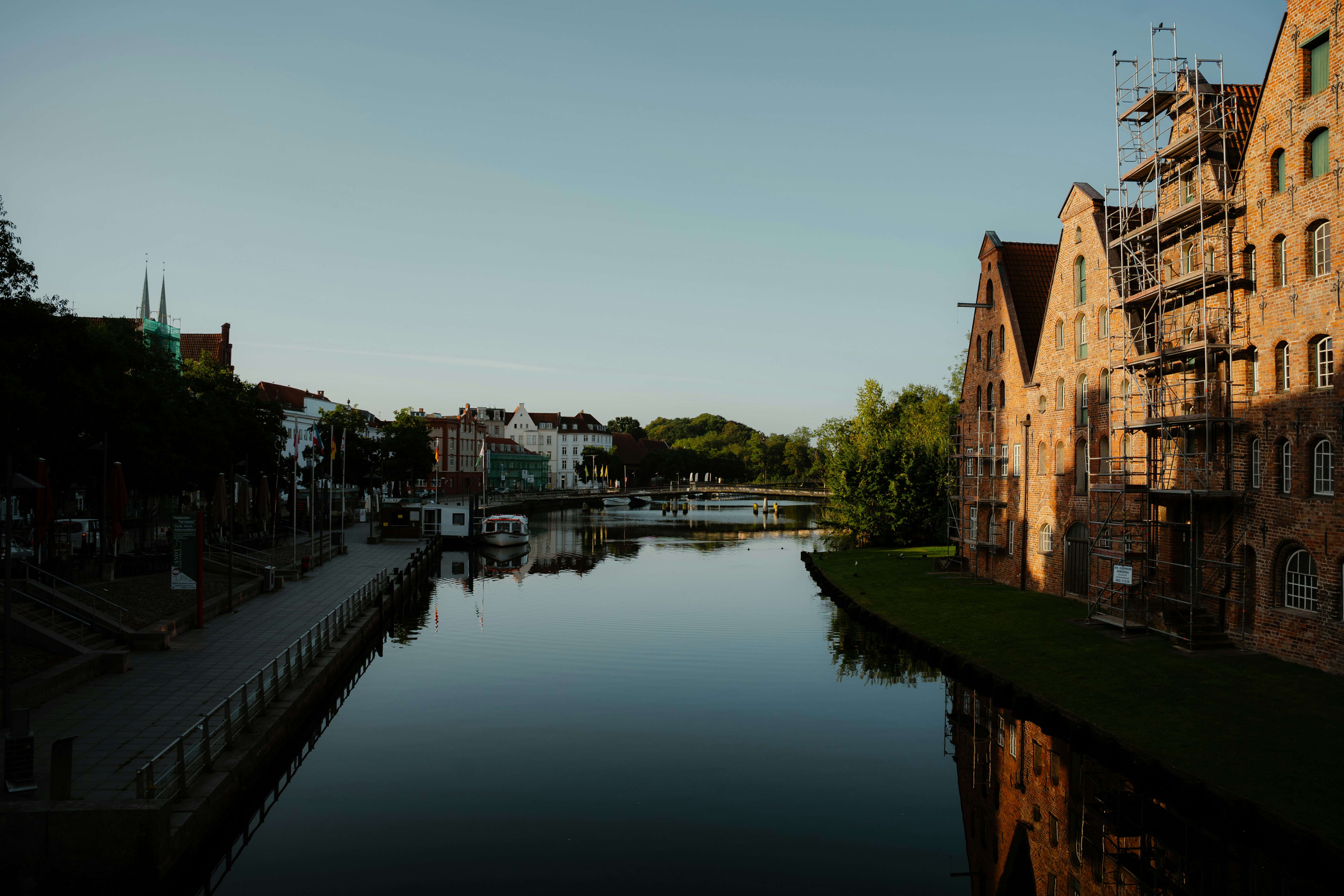 Buildings line a calm river with reflections.