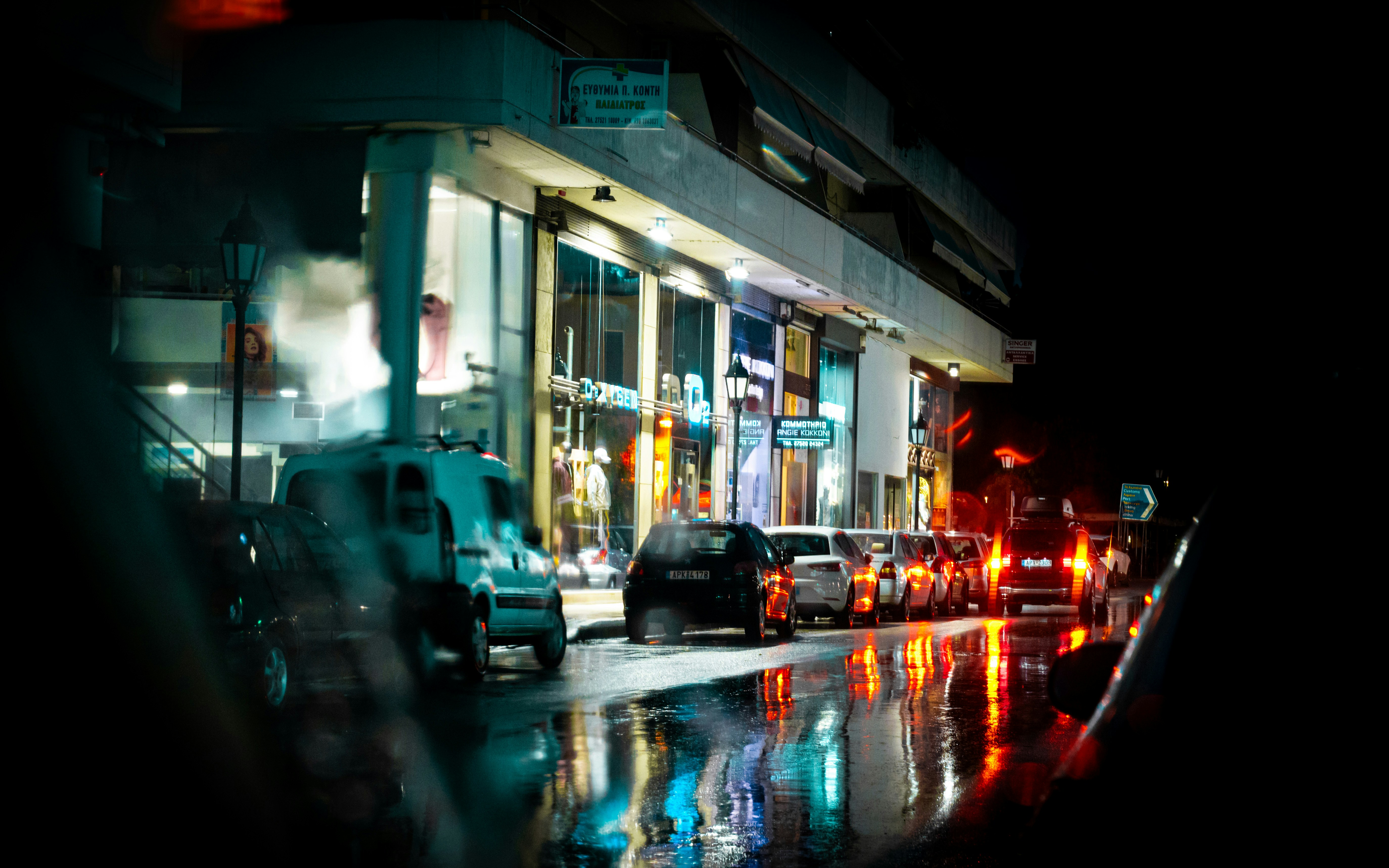 Evening rain reflecting city lights on a street in Nafplio, Greece. | Wet city street at night with reflections