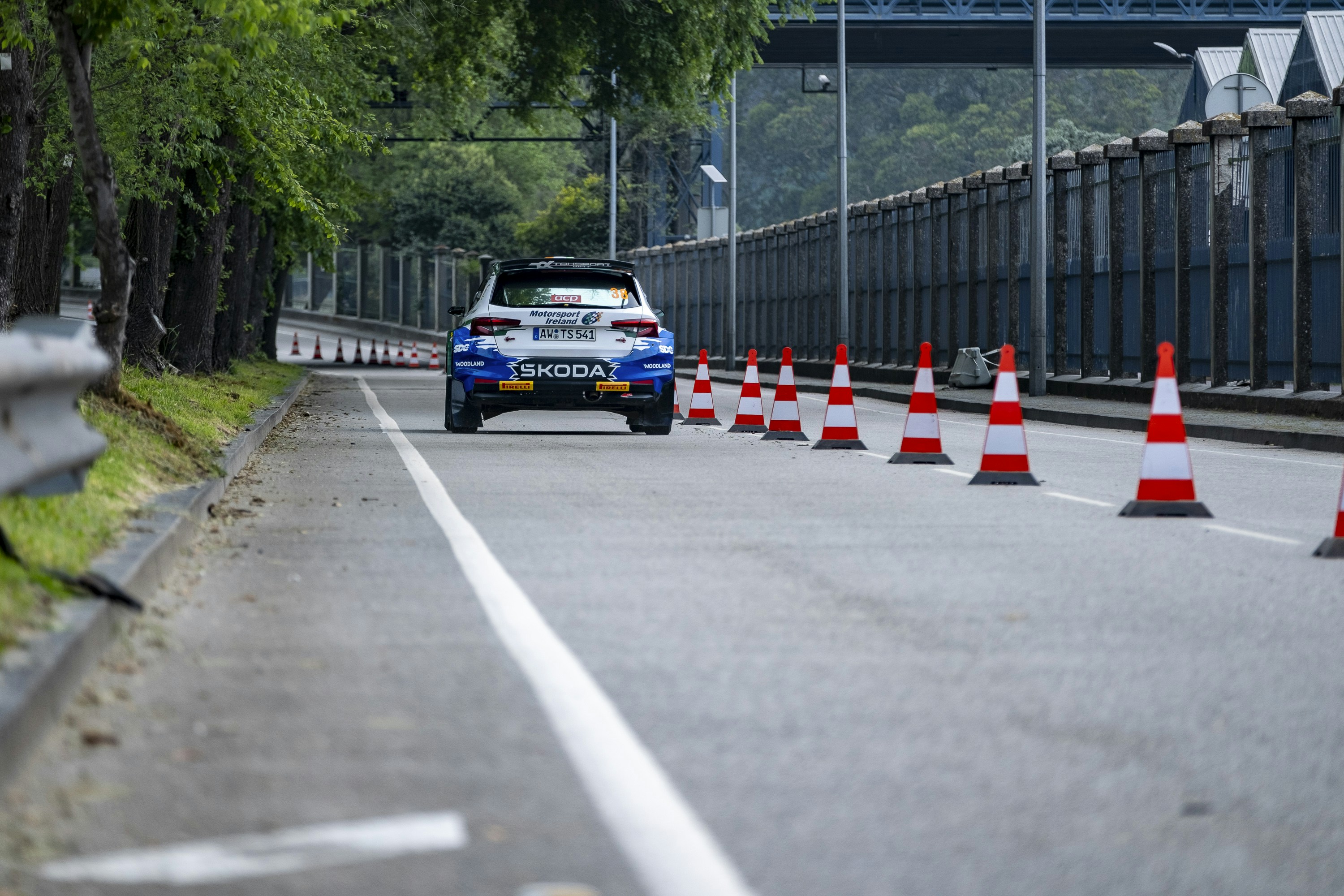 Race car maneuvering through a series of traffic cones on a closed road, showcasing skill and precision during a training session.
