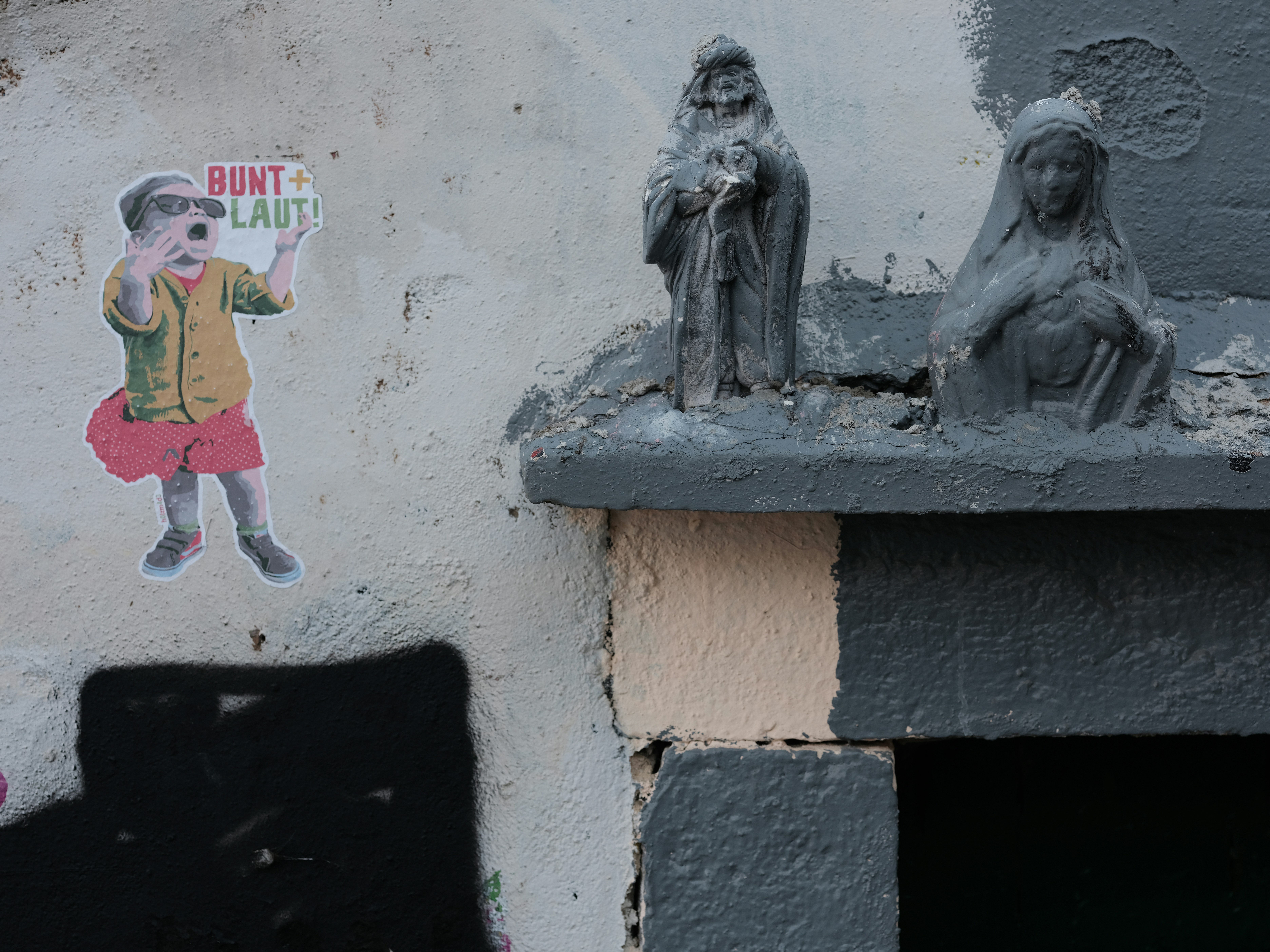 Sticker of boy holding sign next to statues on wall