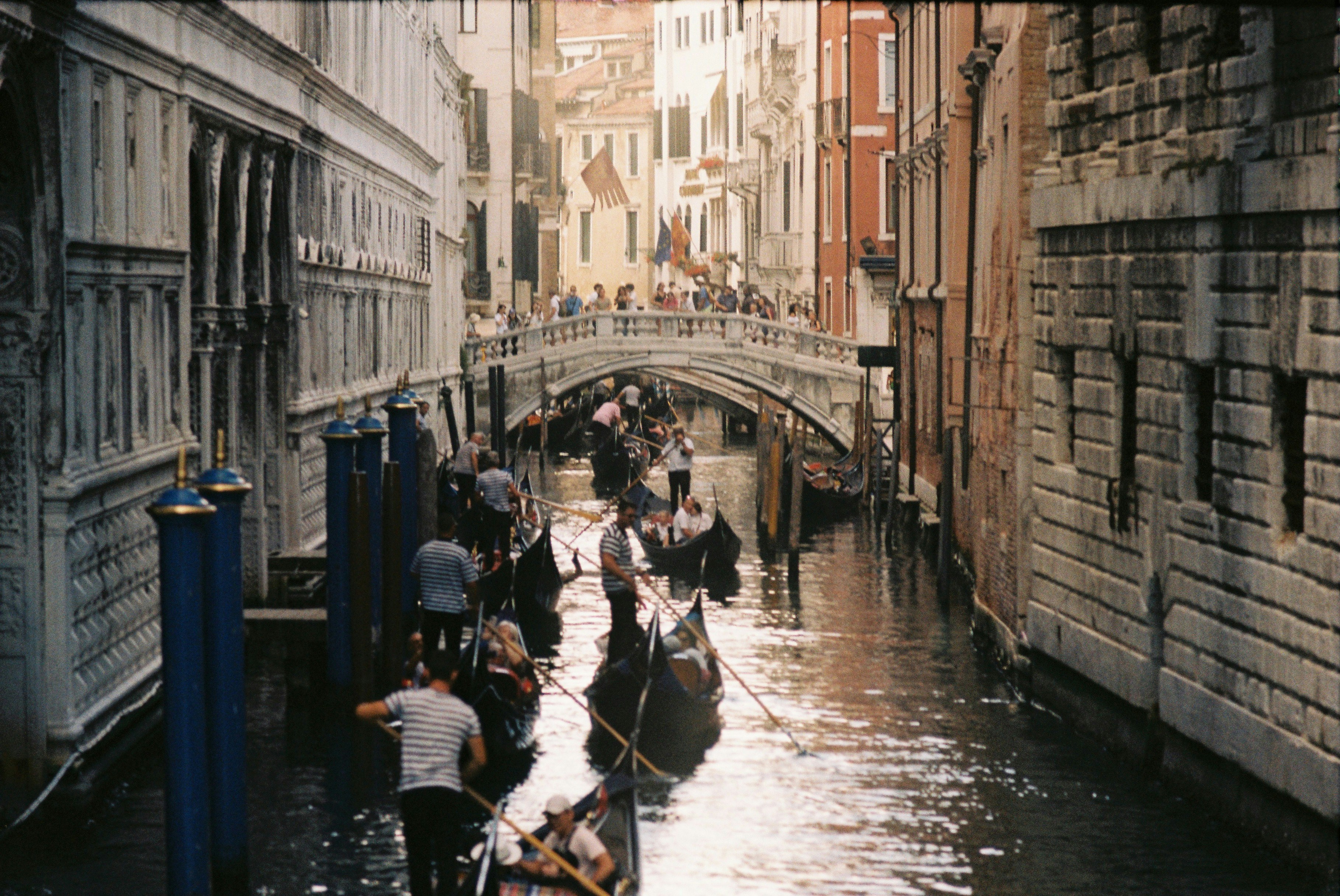 Gondola Parade Under a Weathered Venetian Bridge