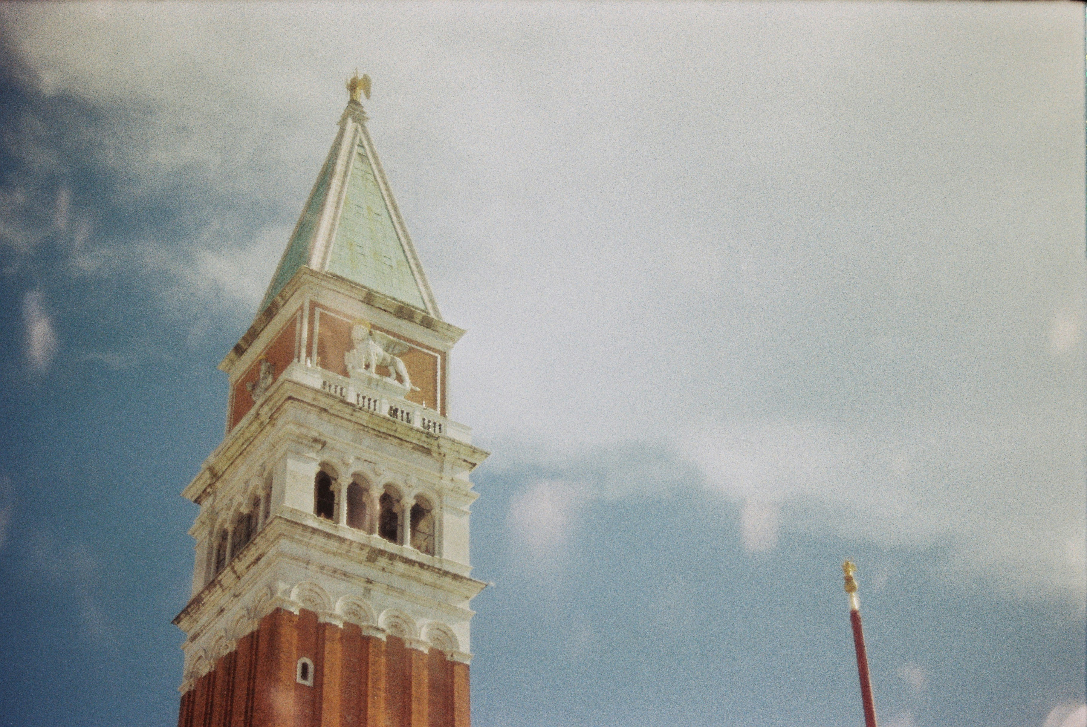 Copper-Crowned Campanile Rising Over Brickwork Under a Bright Sky