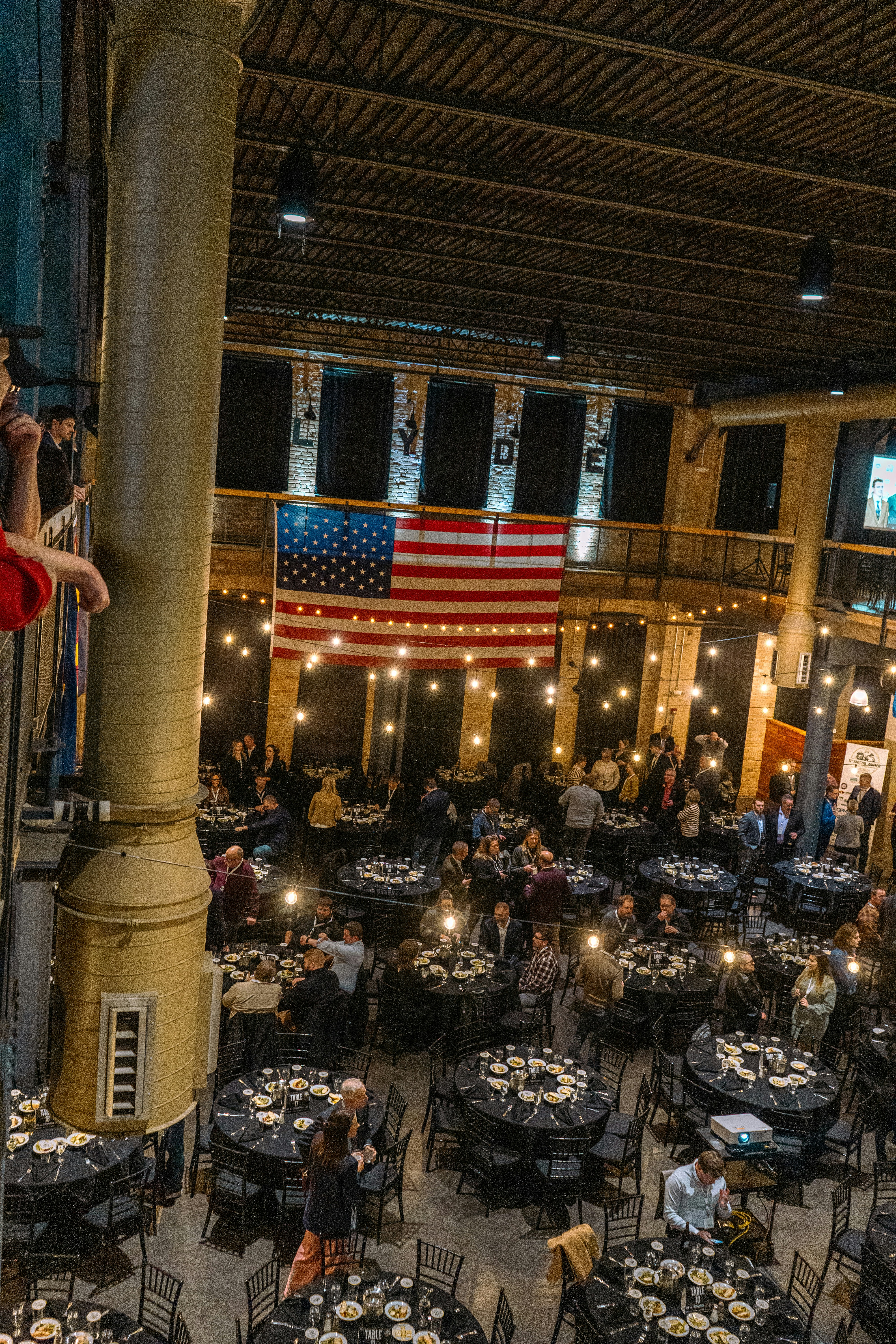 An american flag hangs over a banquet hall event.