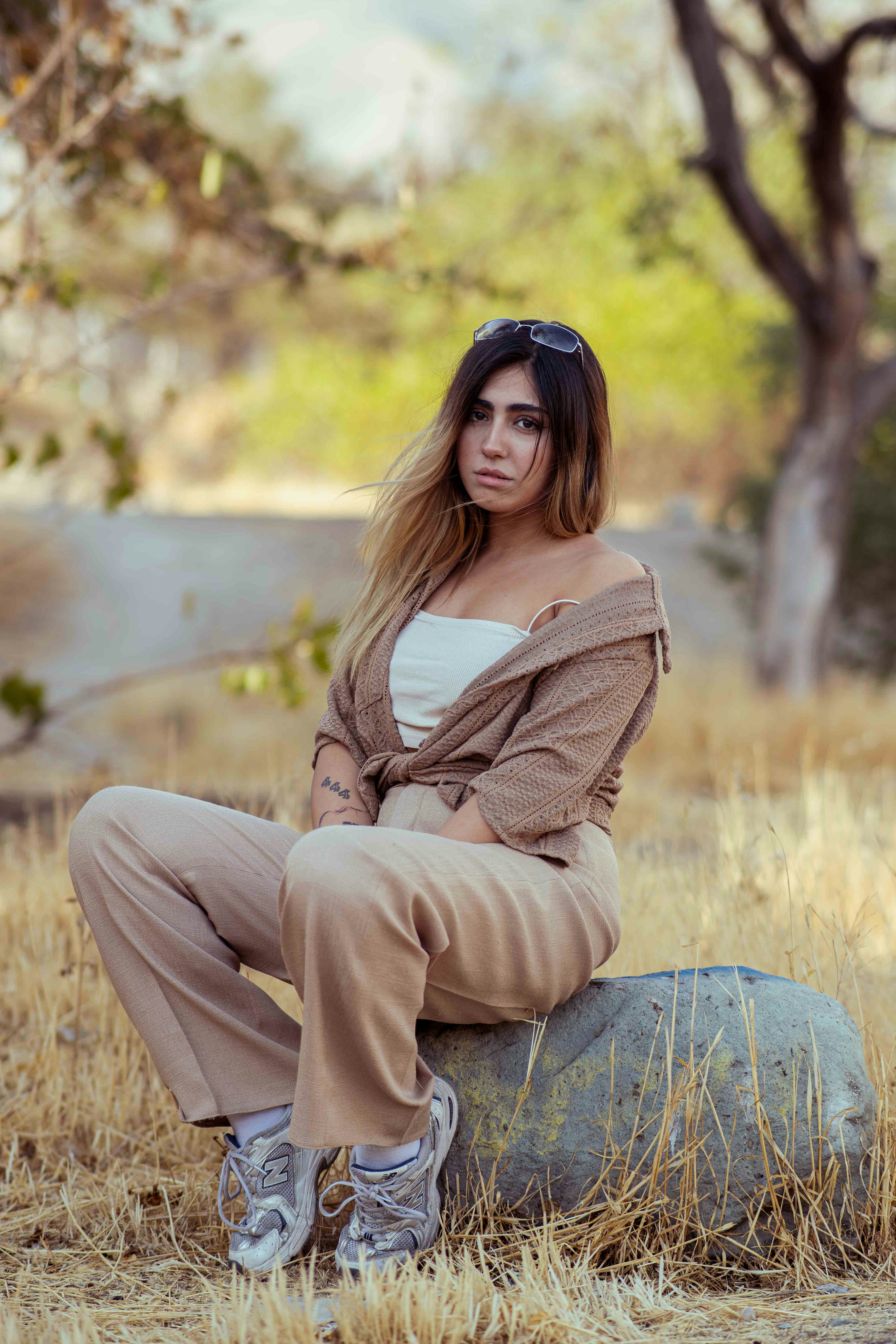 Woman sitting on a rock in dry grass