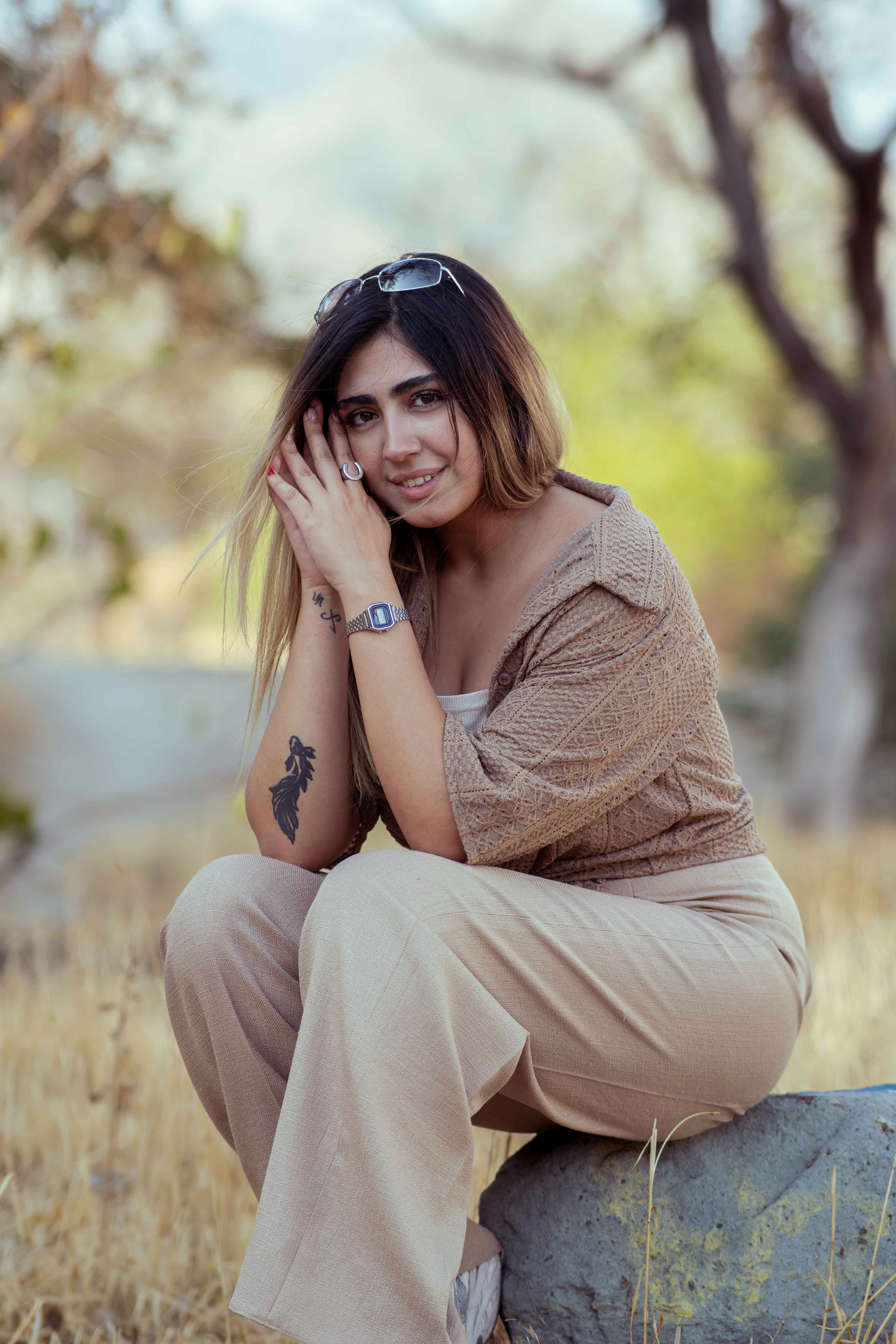 A young woman sitting outdoors on a rock.