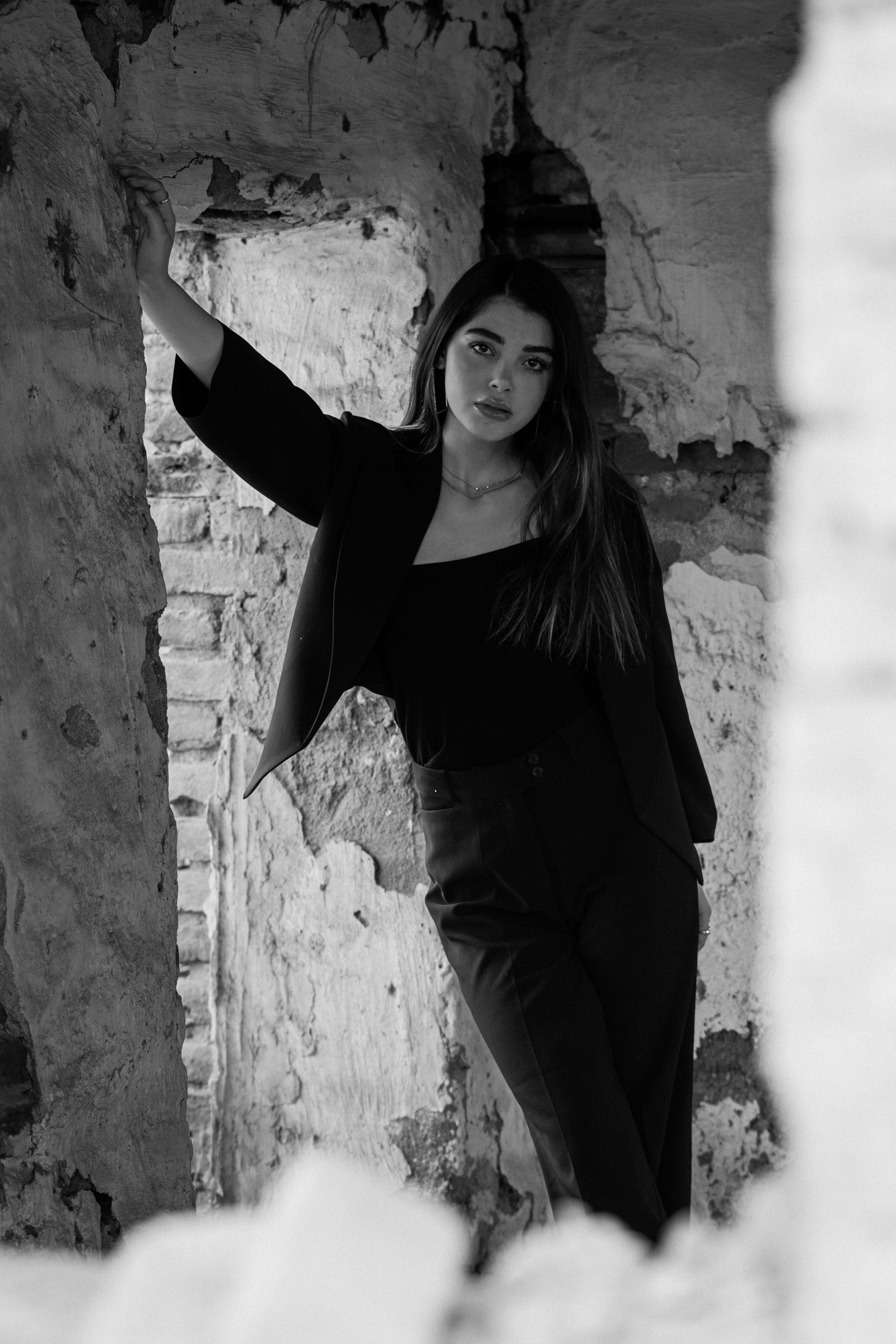 A woman in black stands in a ruined building.