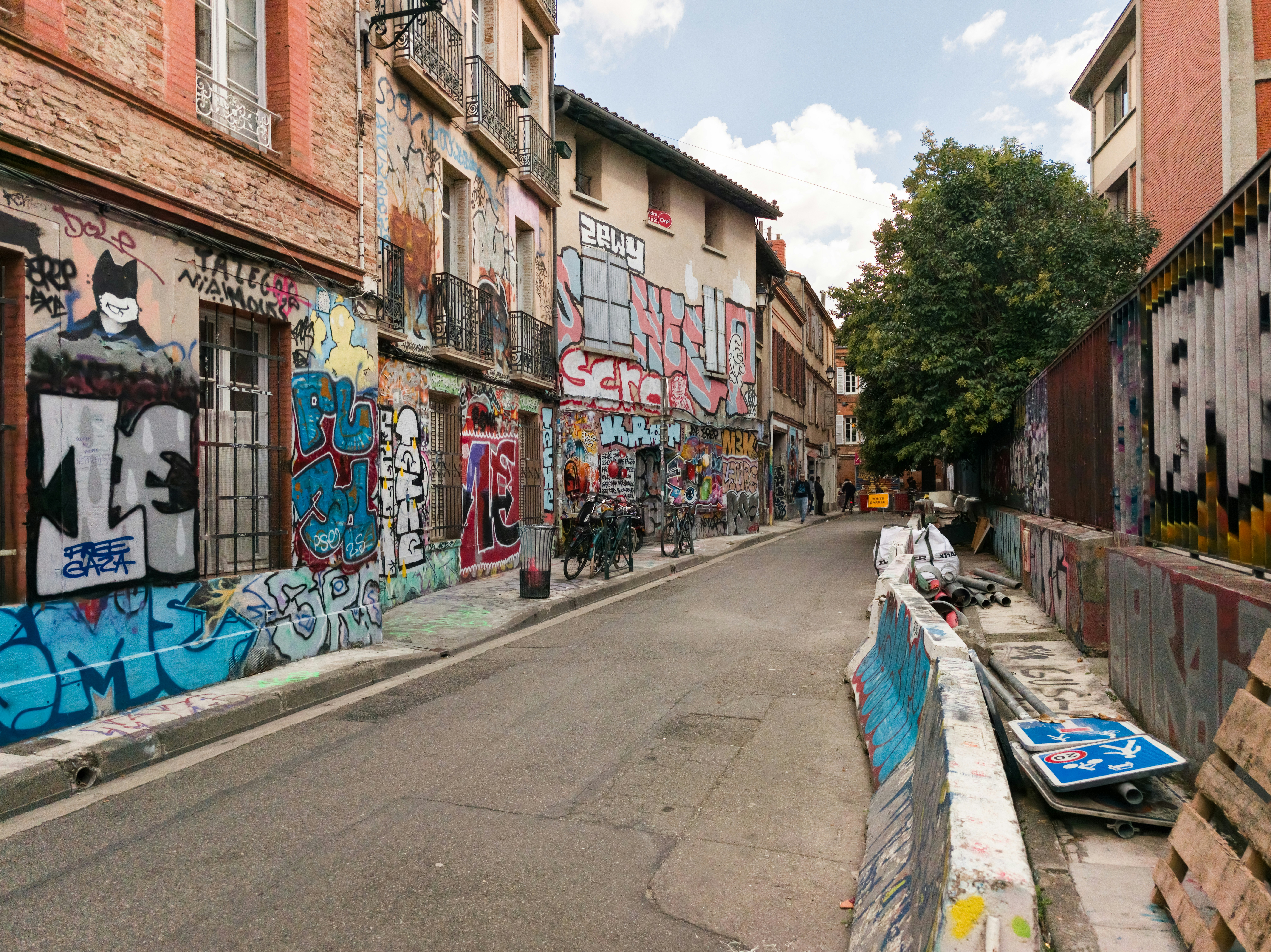 Graffiti-covered buildings line a narrow street. photo – Free Art Image ...