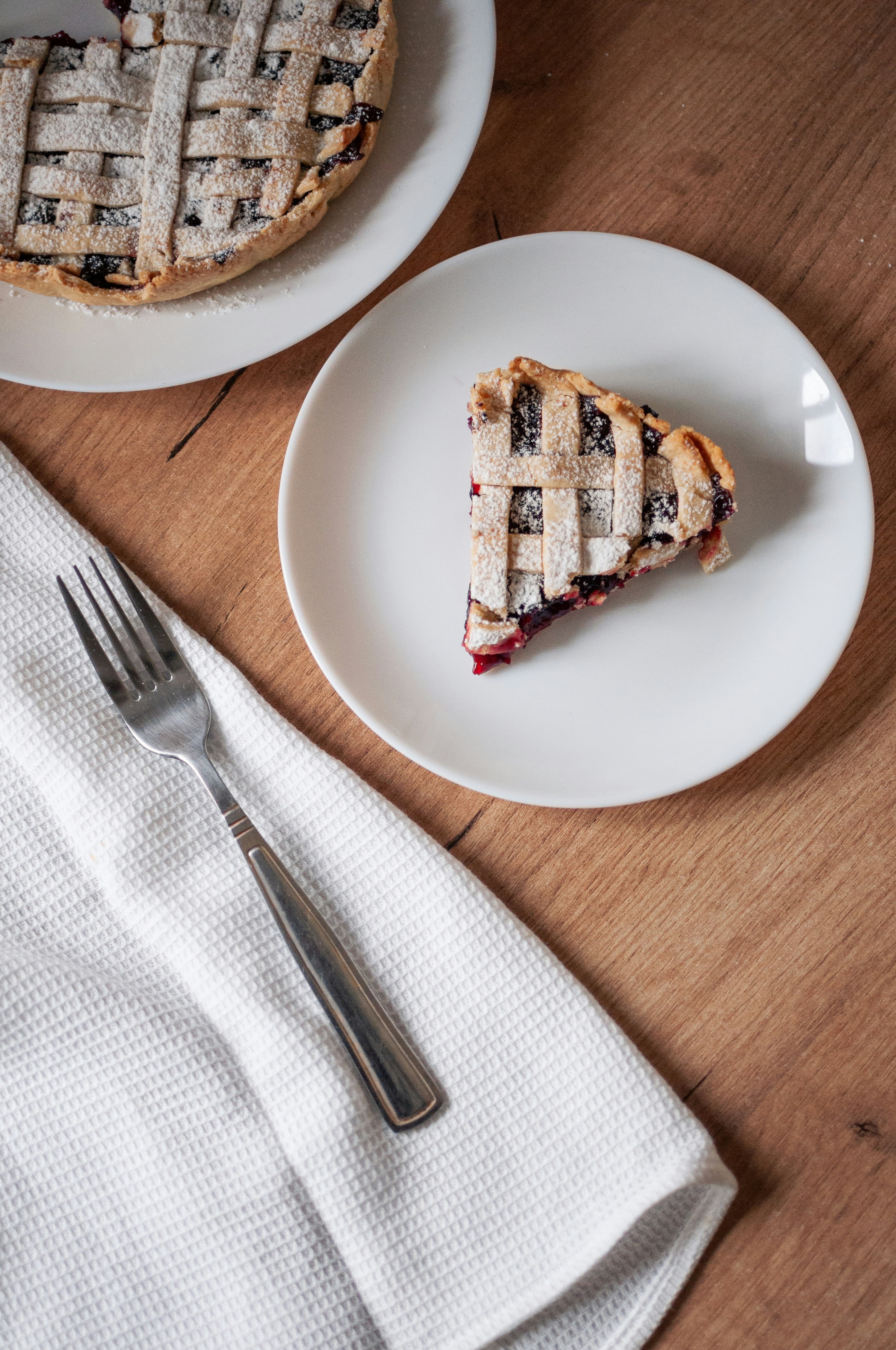 Slice of berry pie on a white plate with fork