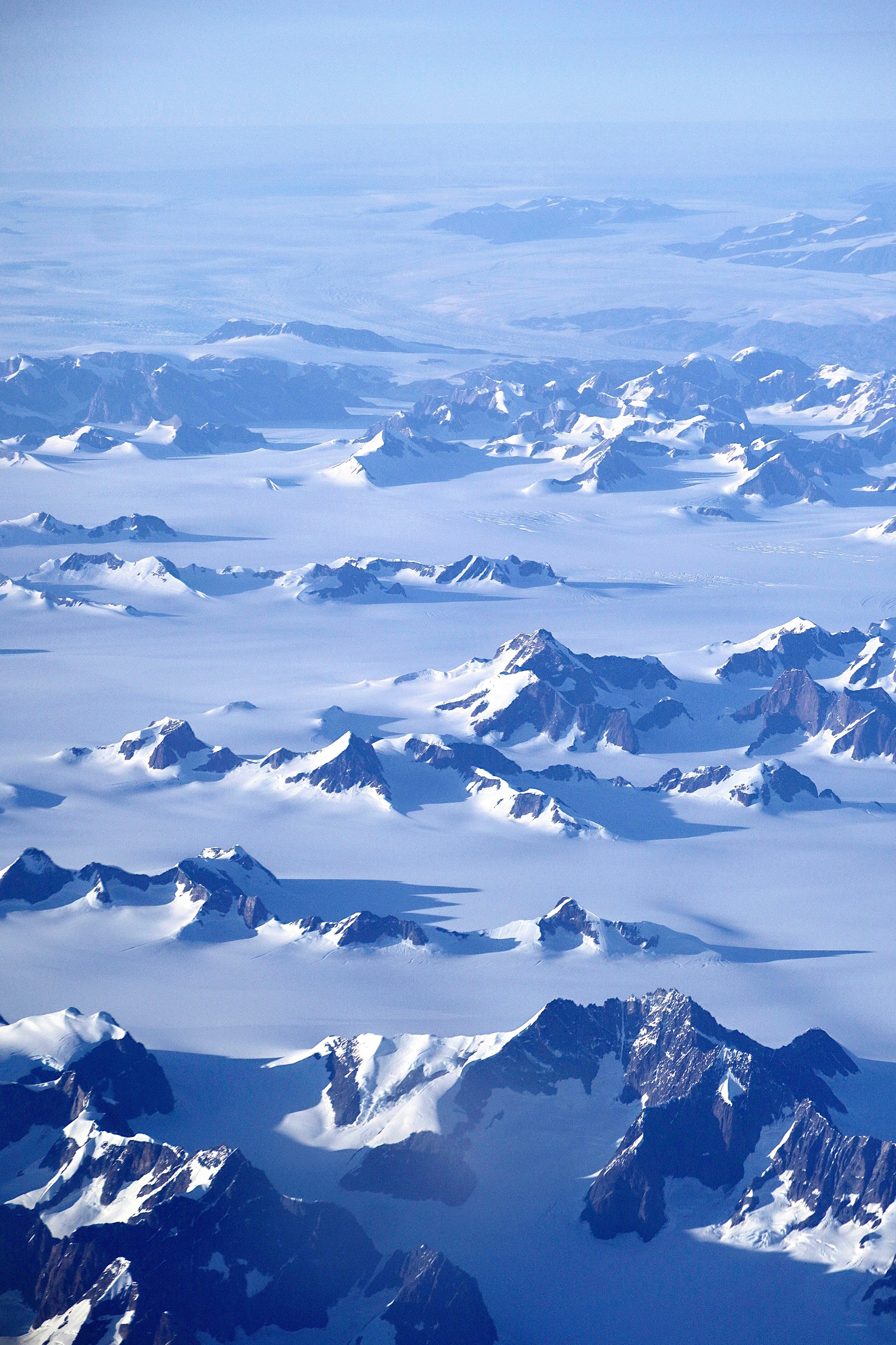 Expansive view of snow-capped mountain ranges blanketed by glacial ice, showcasing the serene beauty of a remote, icy landscape.
