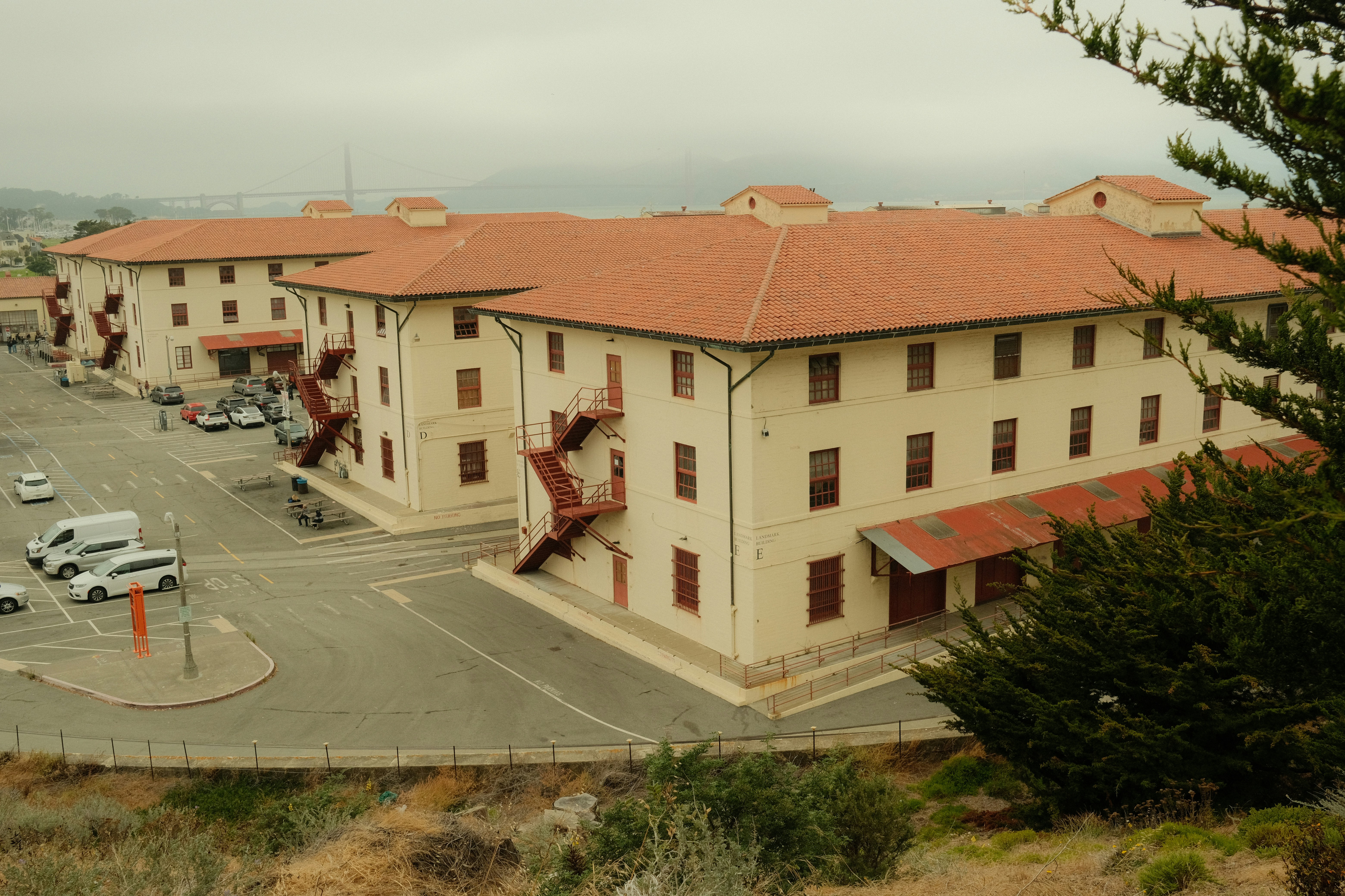 Historic buildings with red-tiled roofs and fire escapes, set against a muted sky. The scene captures a blend of architectural design and natural surroundings.
