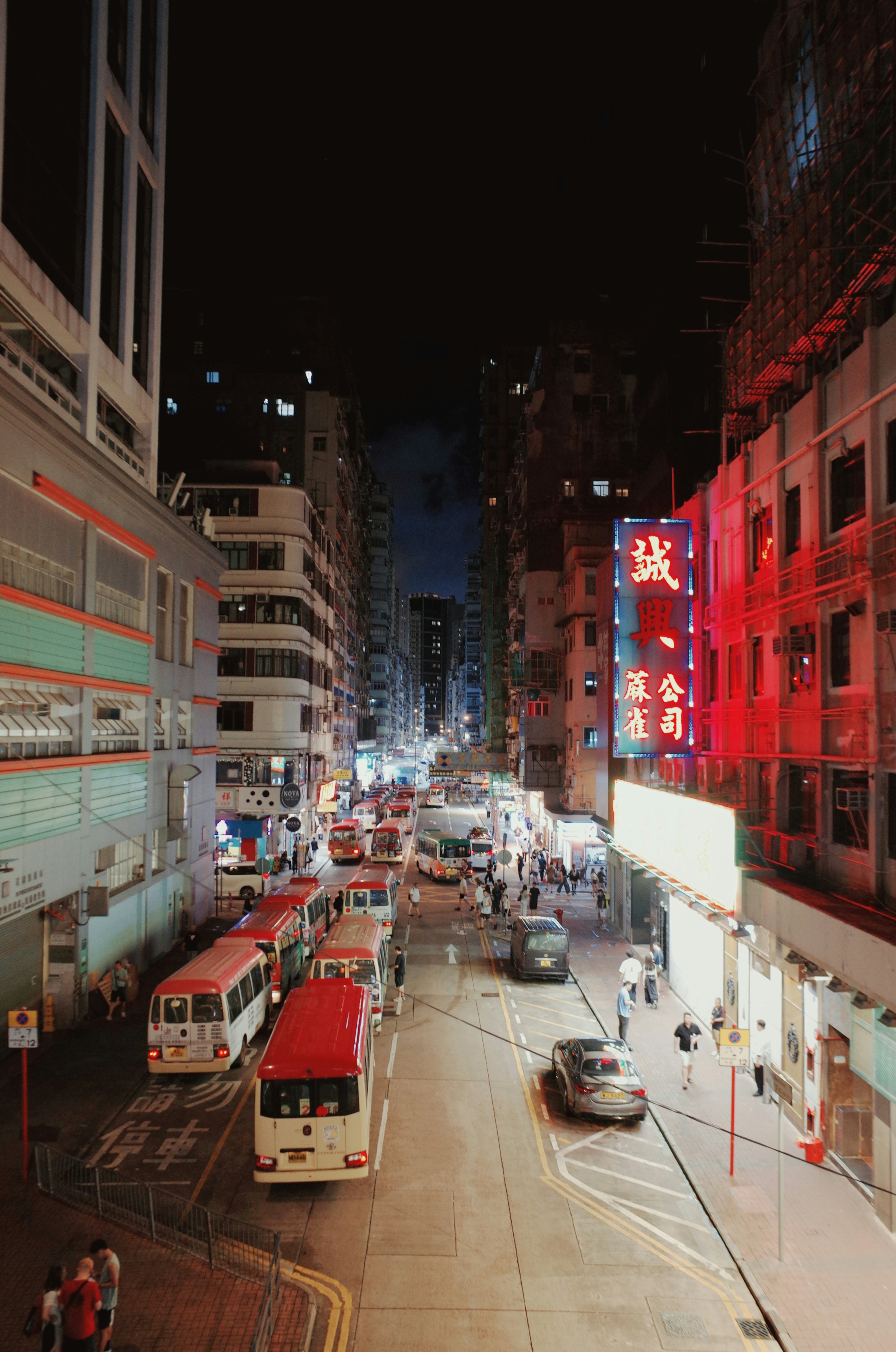 City street with buses and neon signs at night.