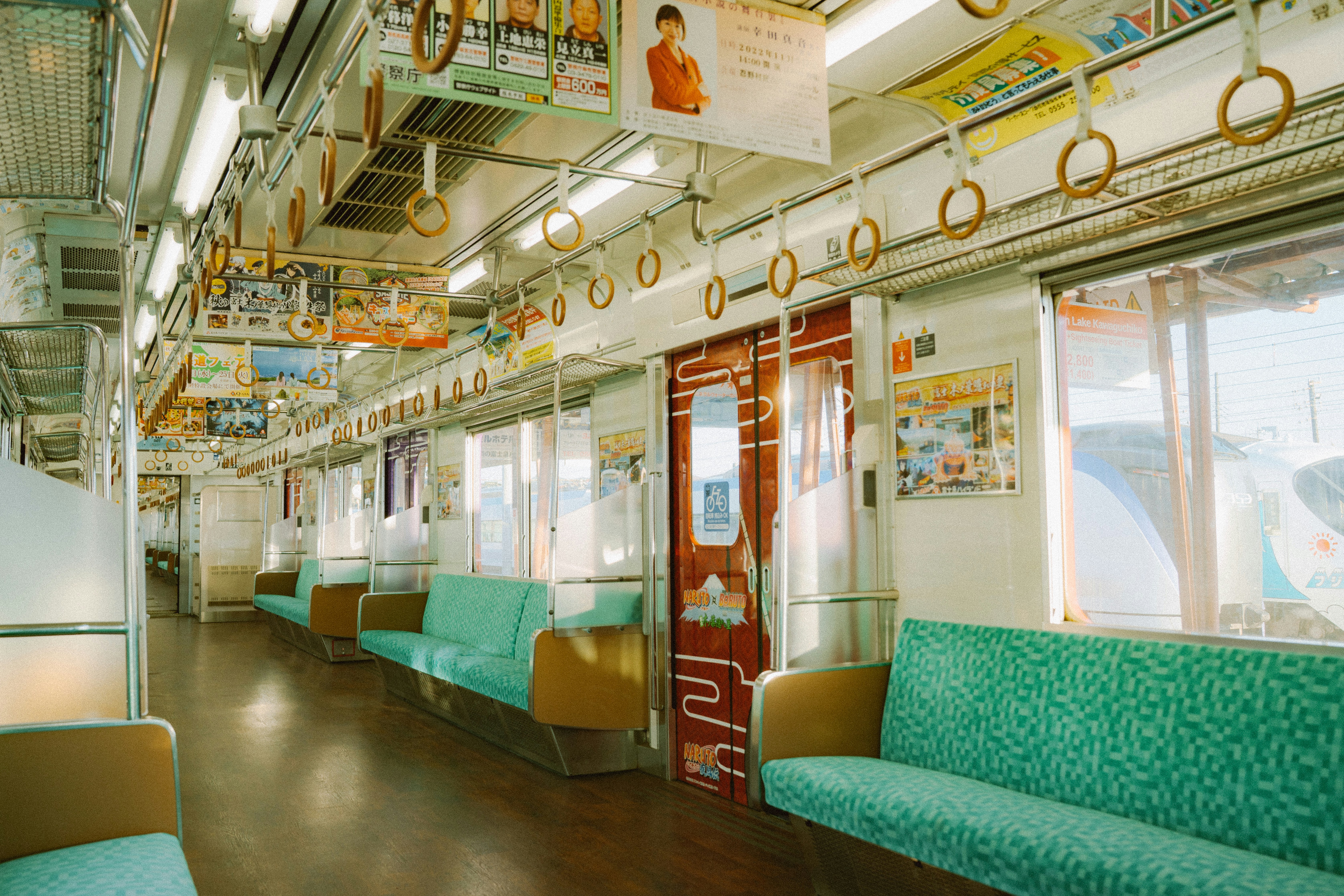 Interior of an empty train carriage with teal seats.