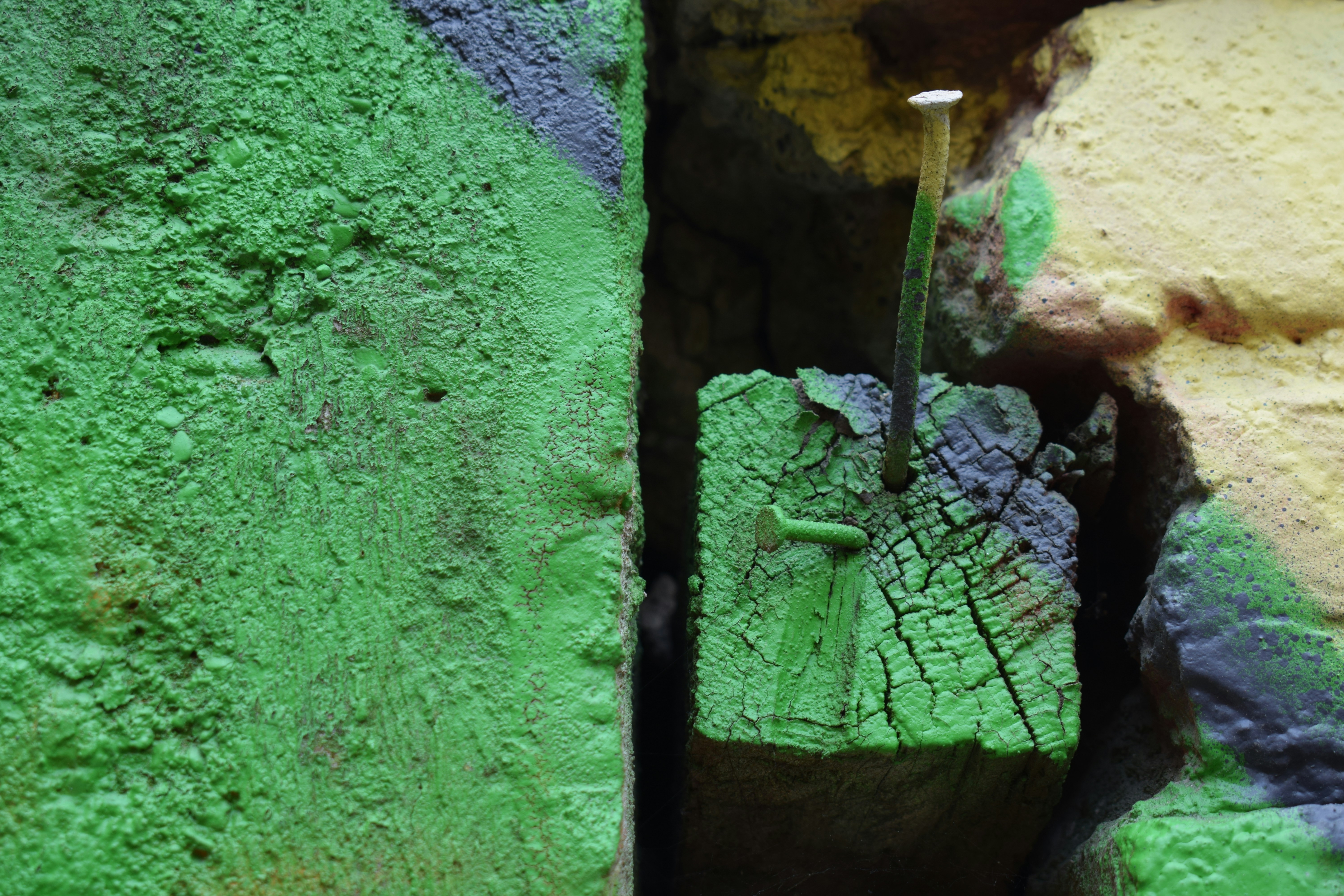 Green painted wood with a nail