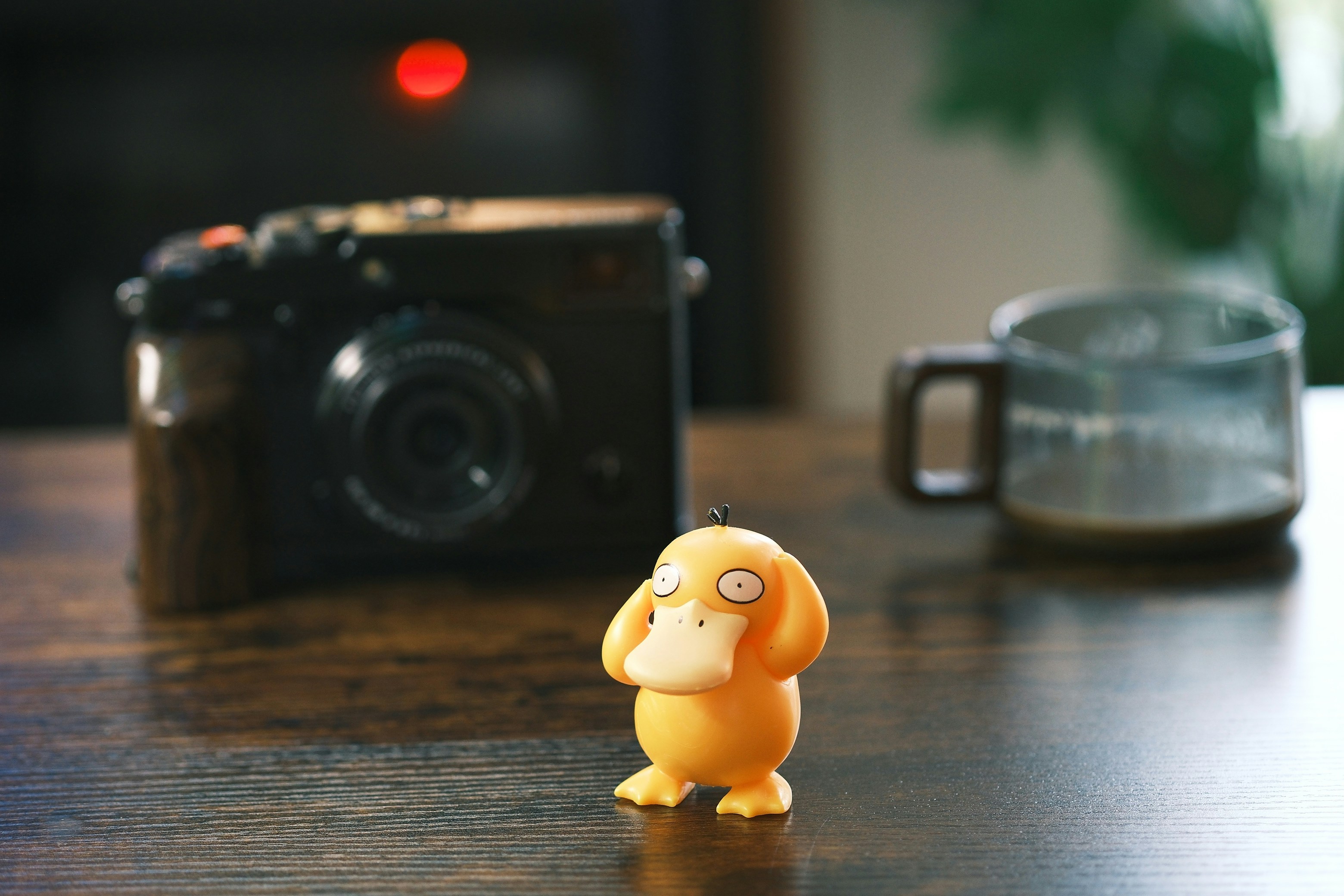 Small yellow duck figurine near camera and mug.