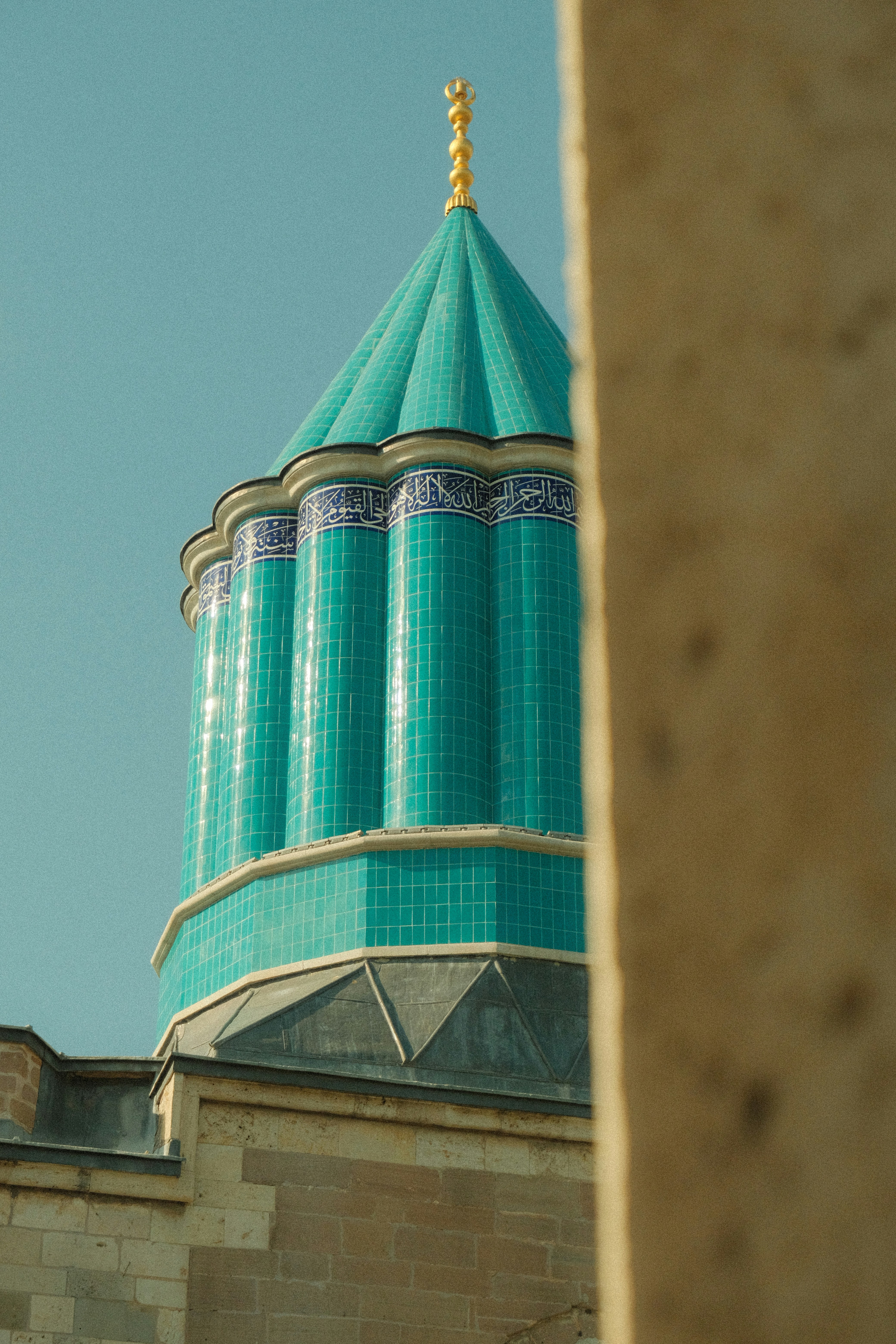 Turquoise tiled dome with golden finial against sky
