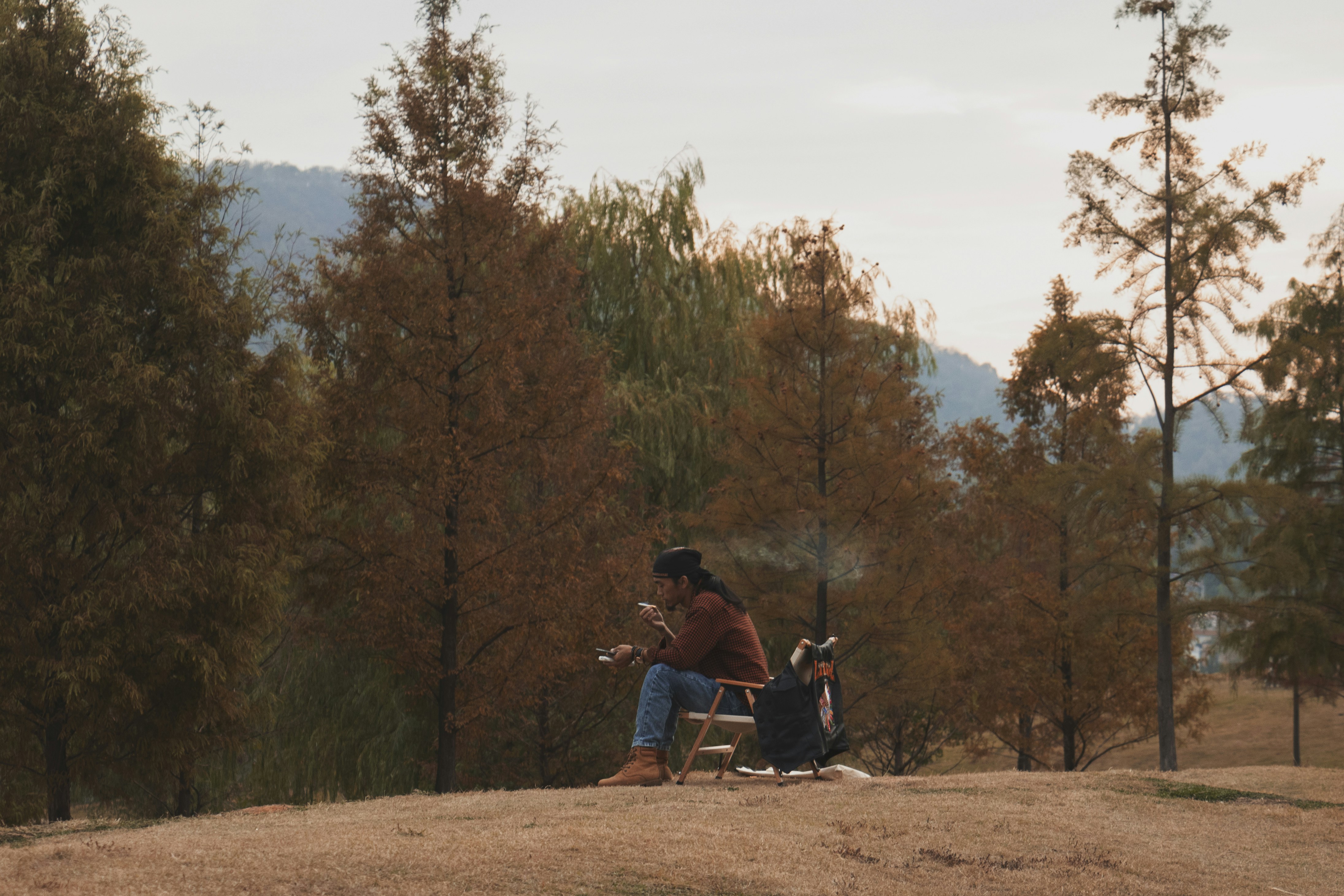 Woman sitting on park bench with autumn trees
