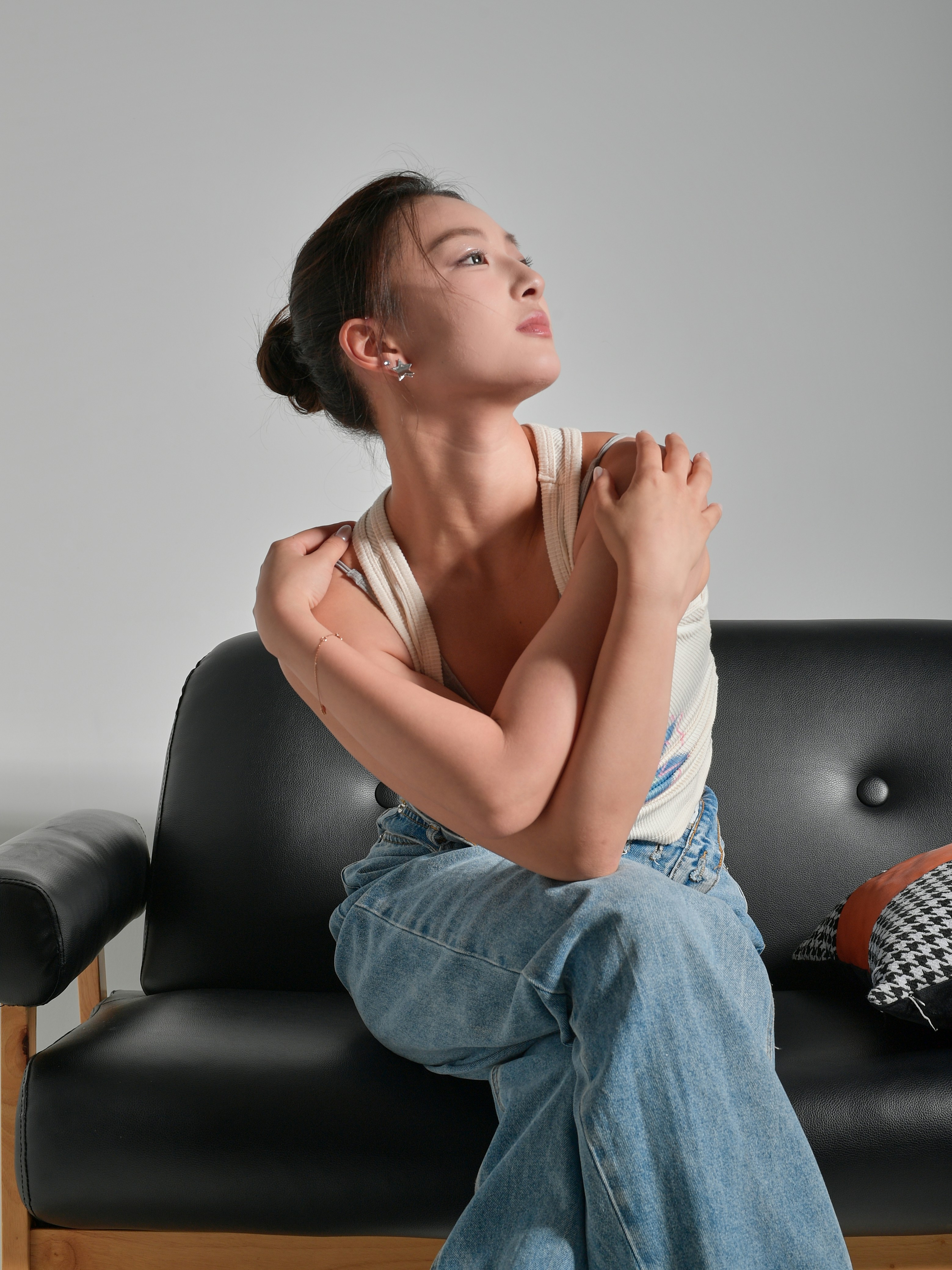 A woman sits on a black couch with arms crossed.