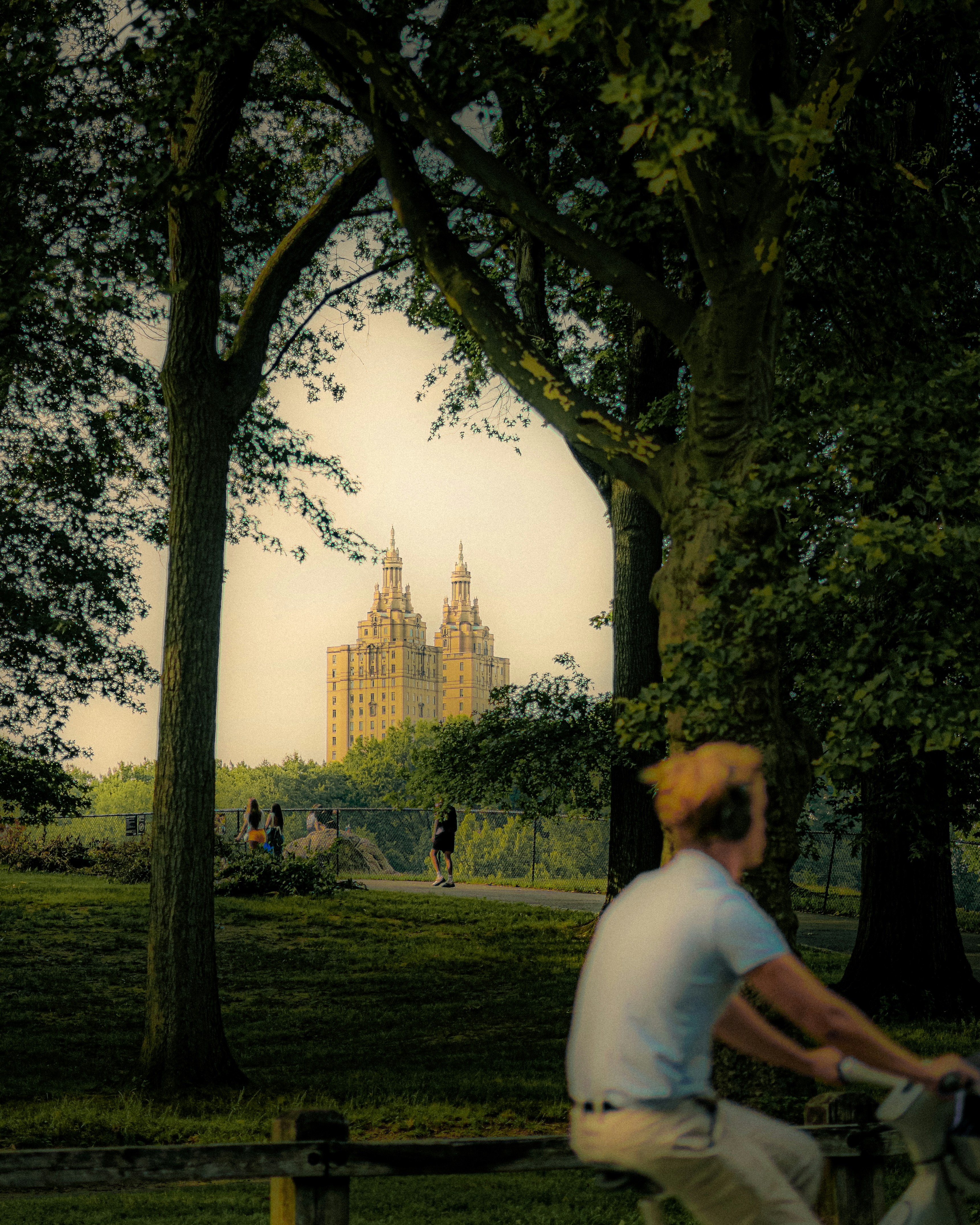 Man rides bicycle past distant castle-like building.