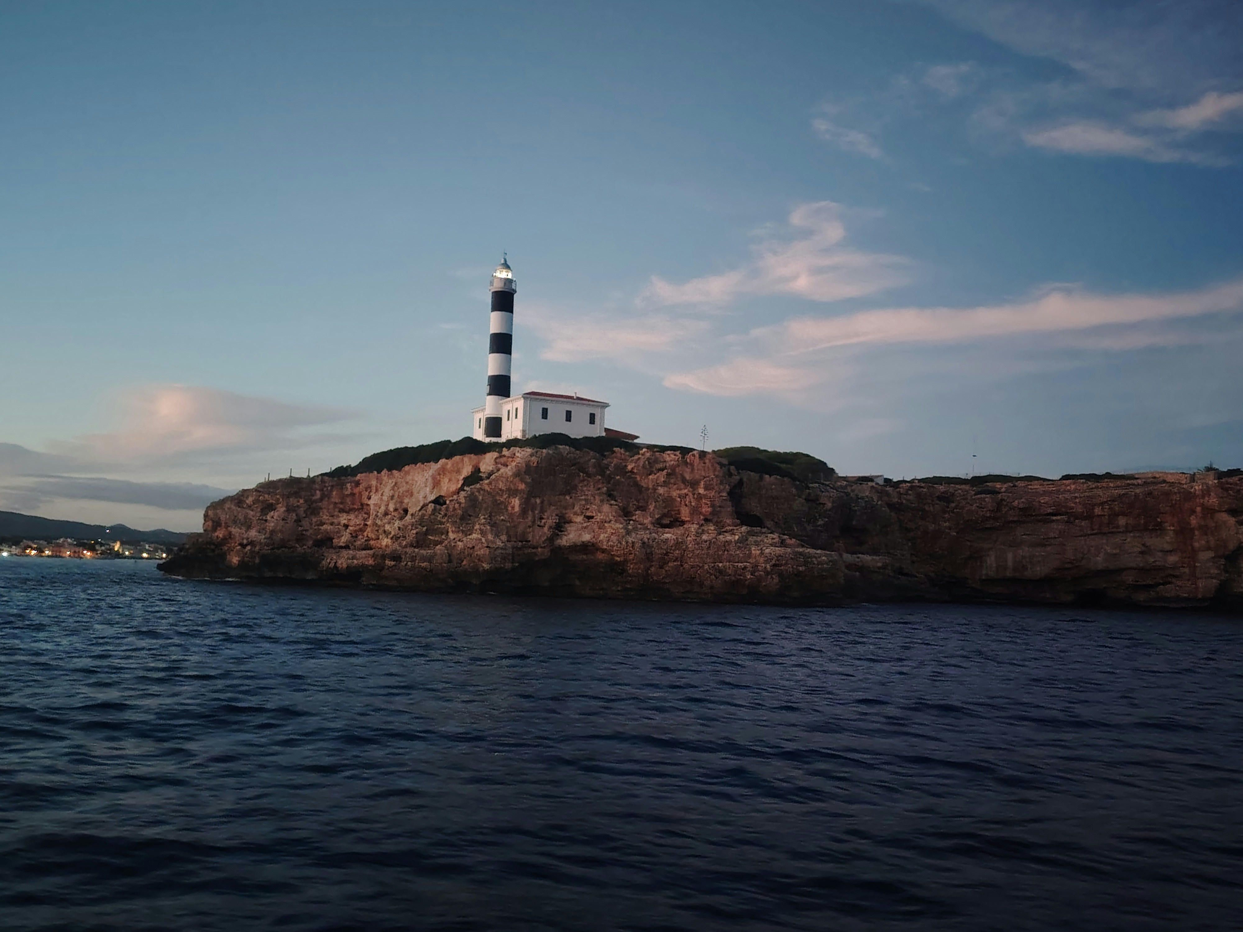 Far de Portocolom/Portocolom Lighthouse | Lighthouse on a rocky island at dusk