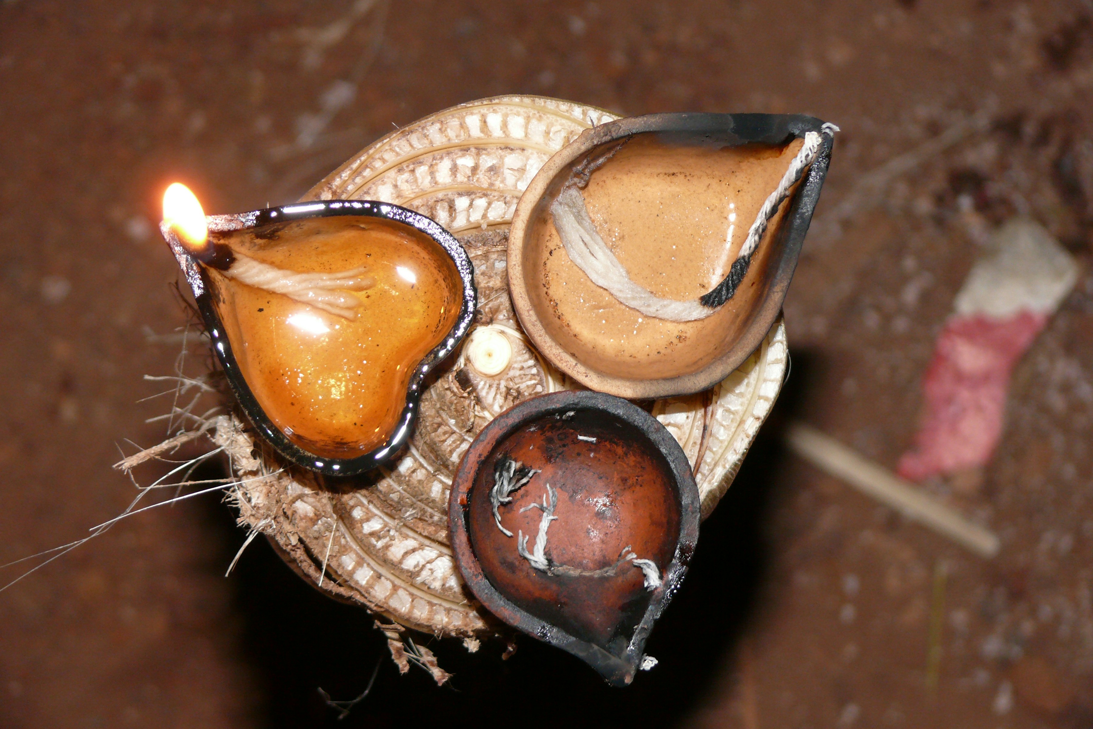 Three clay oil lamps on a wooden surface