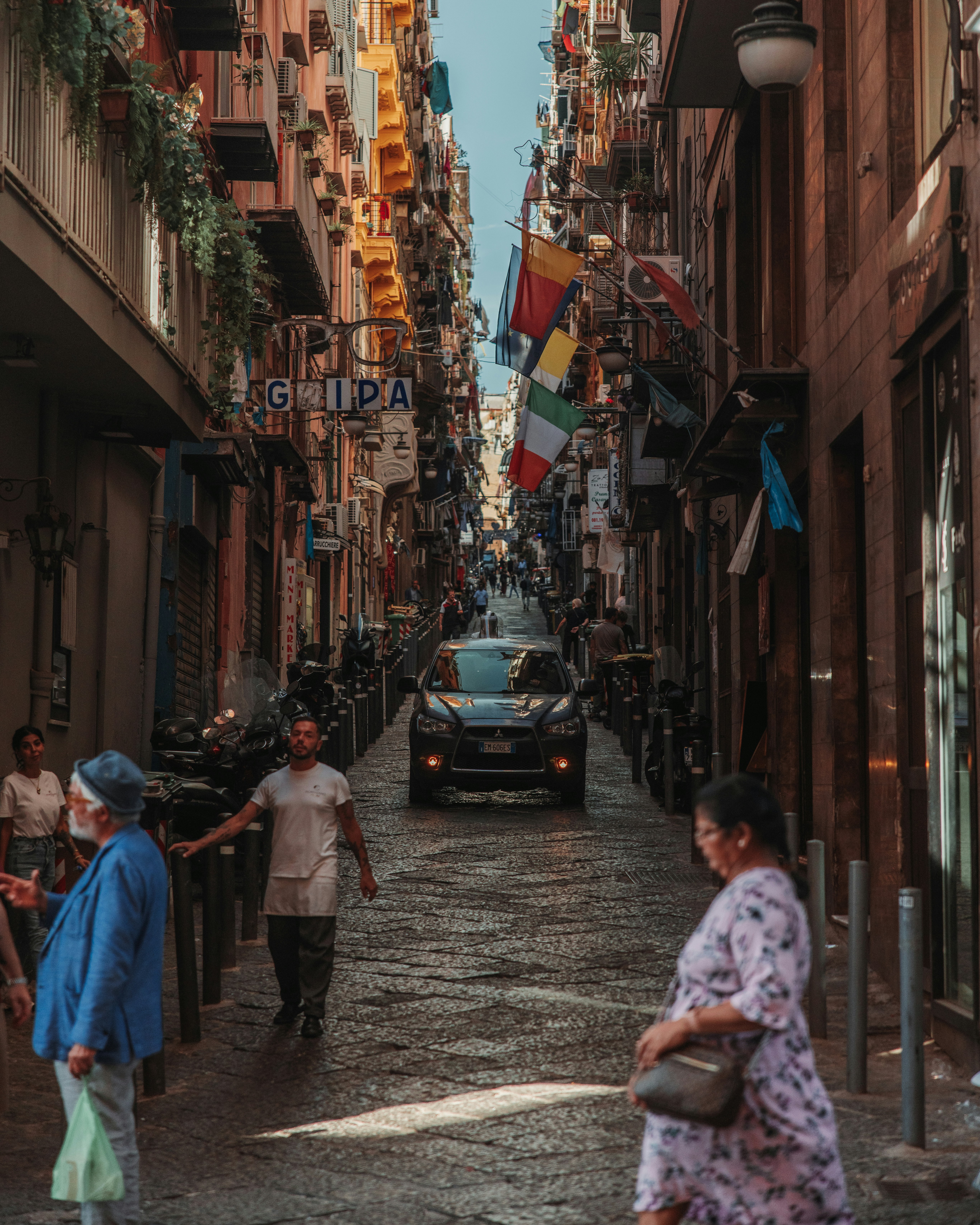 Narrow european street with people and car.