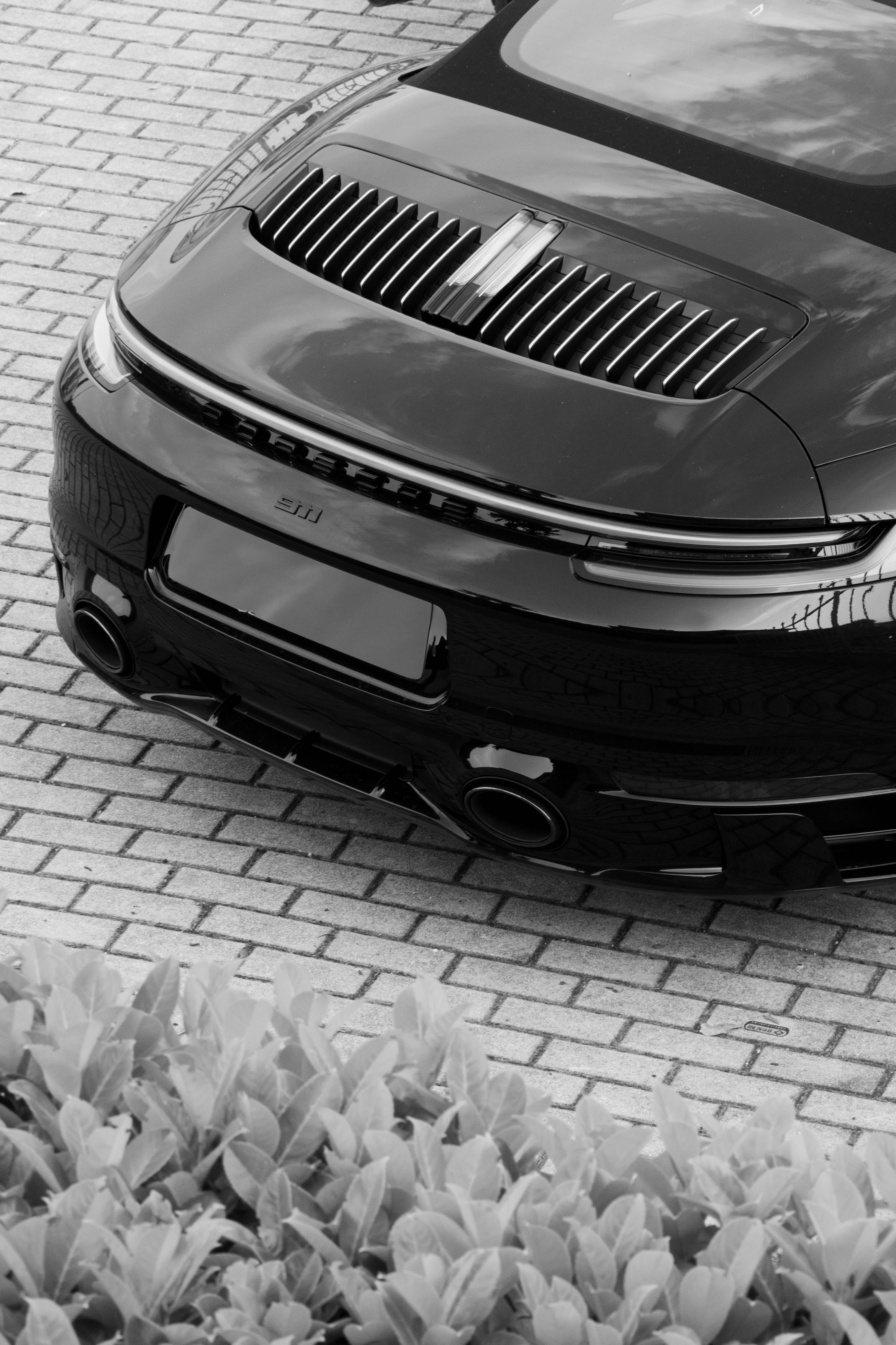 Sleek black sports car captured from above, showcasing its aerodynamic lines and distinctive rear features. The image highlights the intricate design elements of the vehicle.