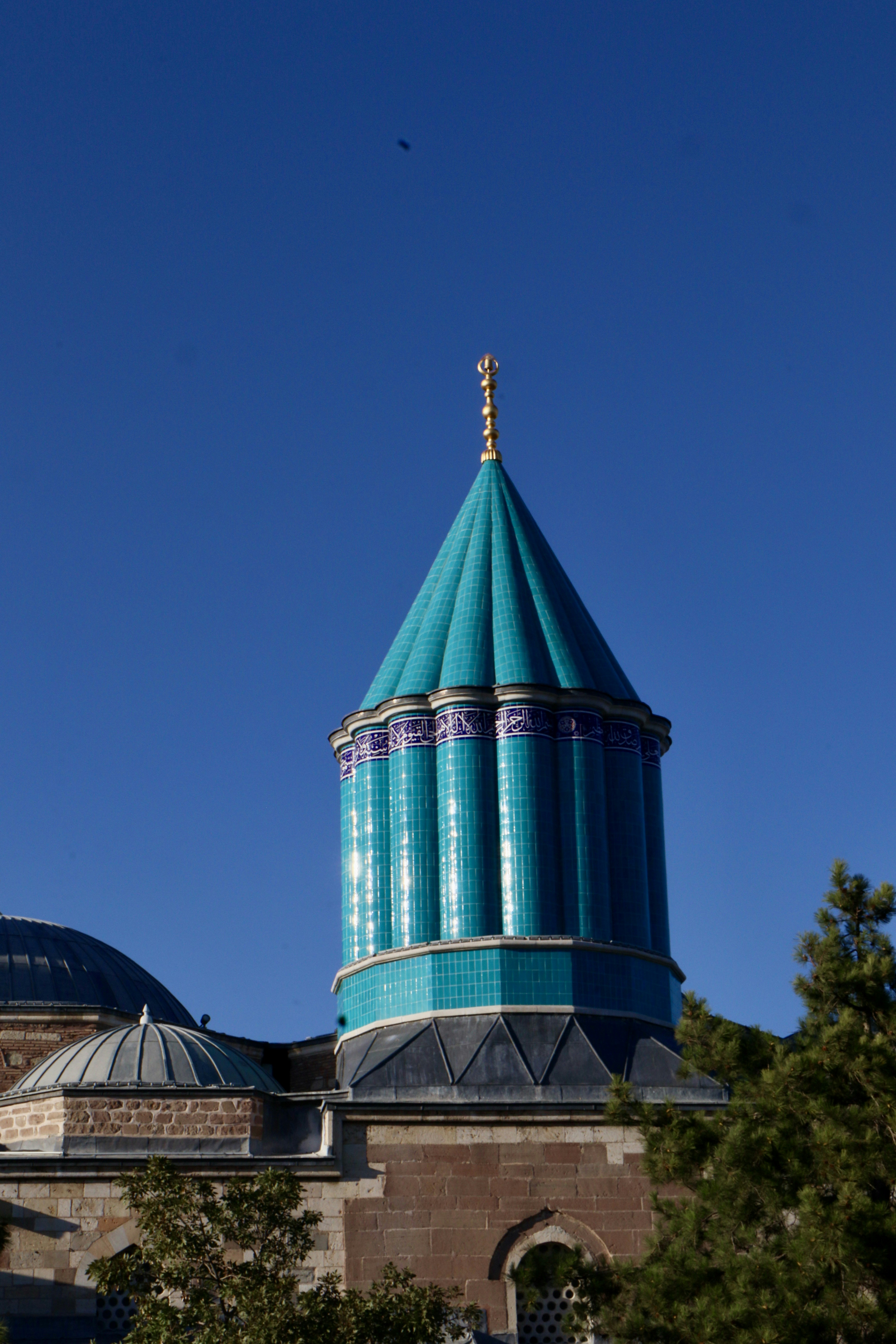 Turquoise Spire Soaring Over Brick Domes Under a Clear Blue Sky