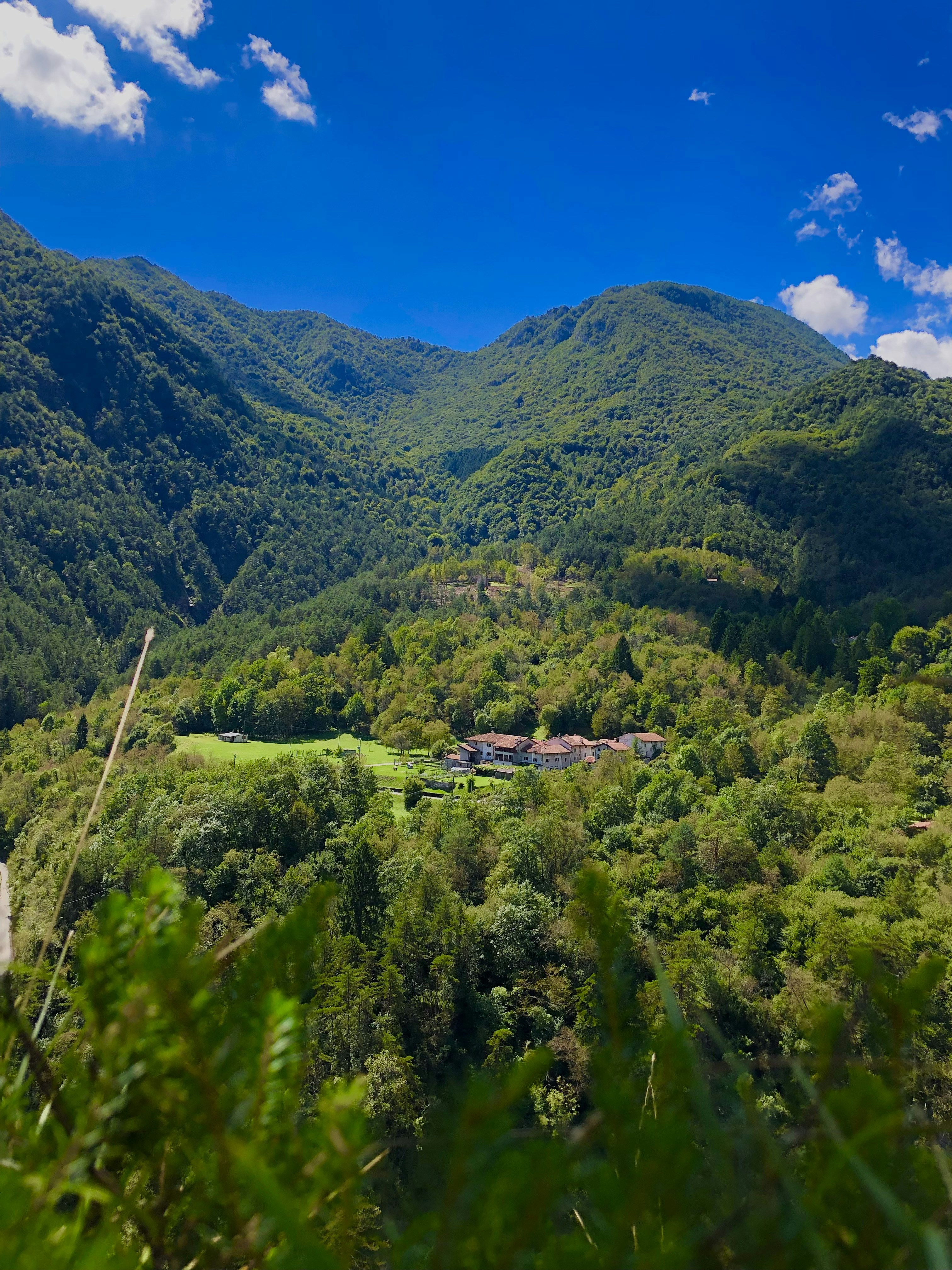 Green mountains with a small village under a blue sky