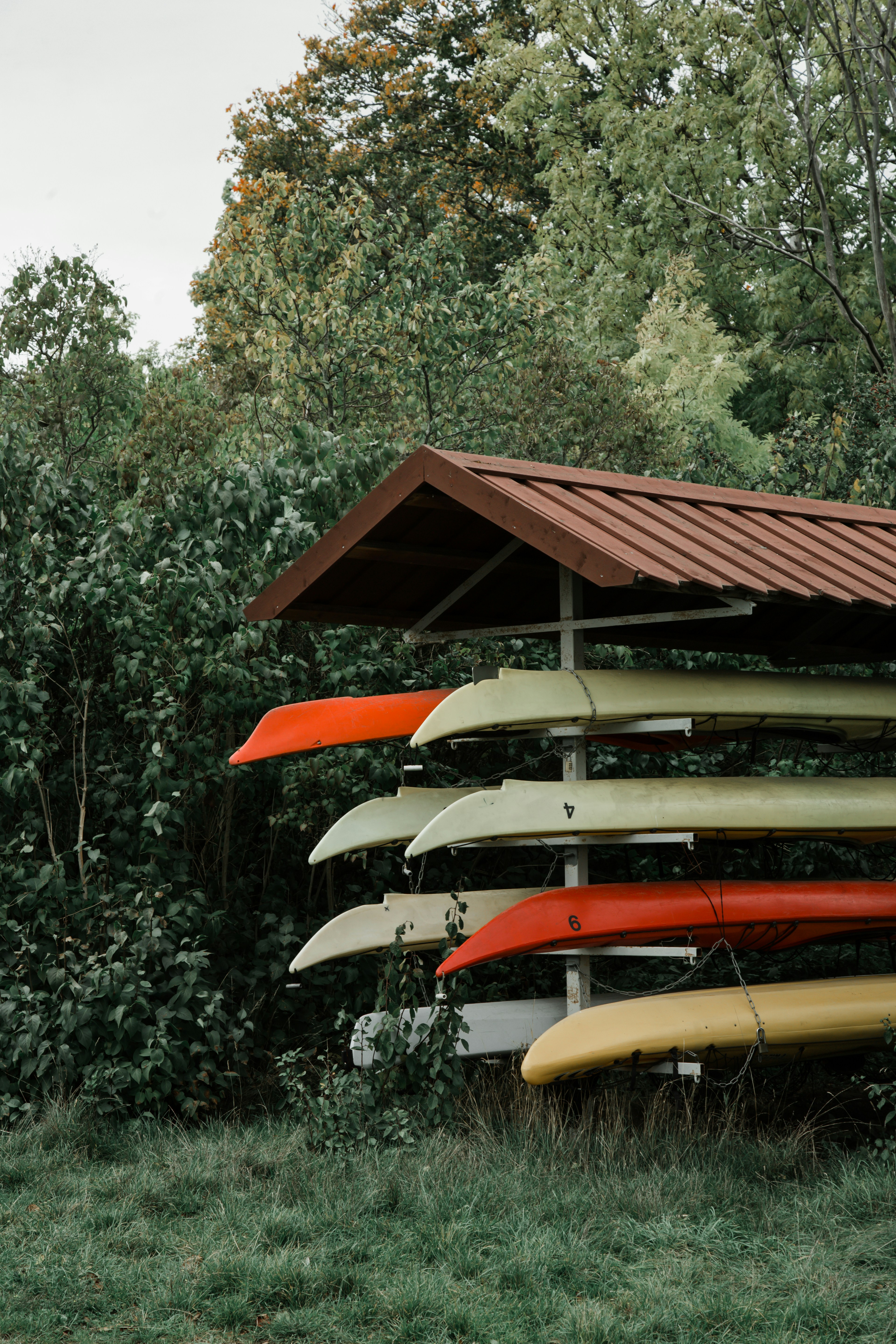 Colorful Kayak Stack Under a Red Roof Amid Greenery