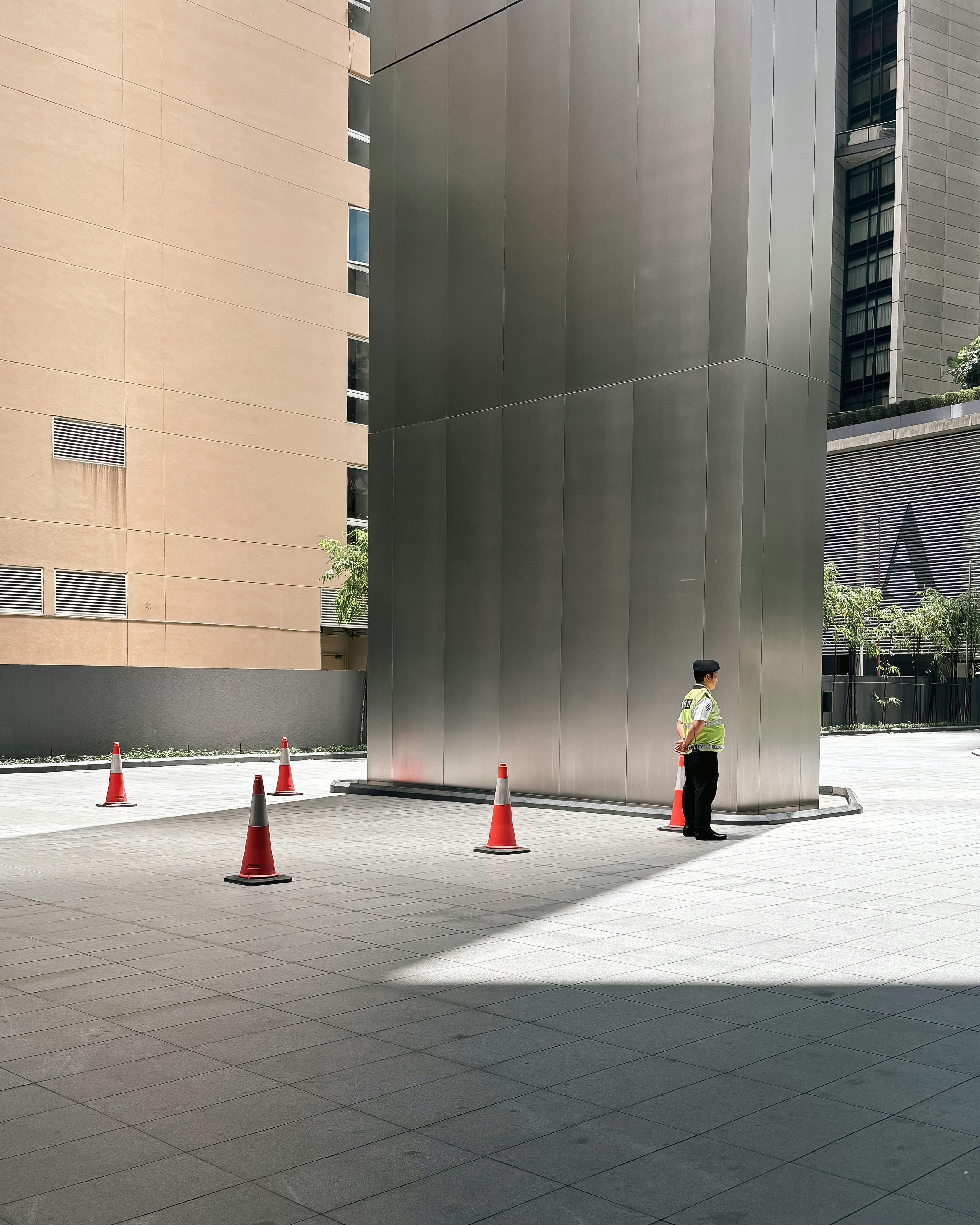 Person standing by a large metal structure with traffic cones.