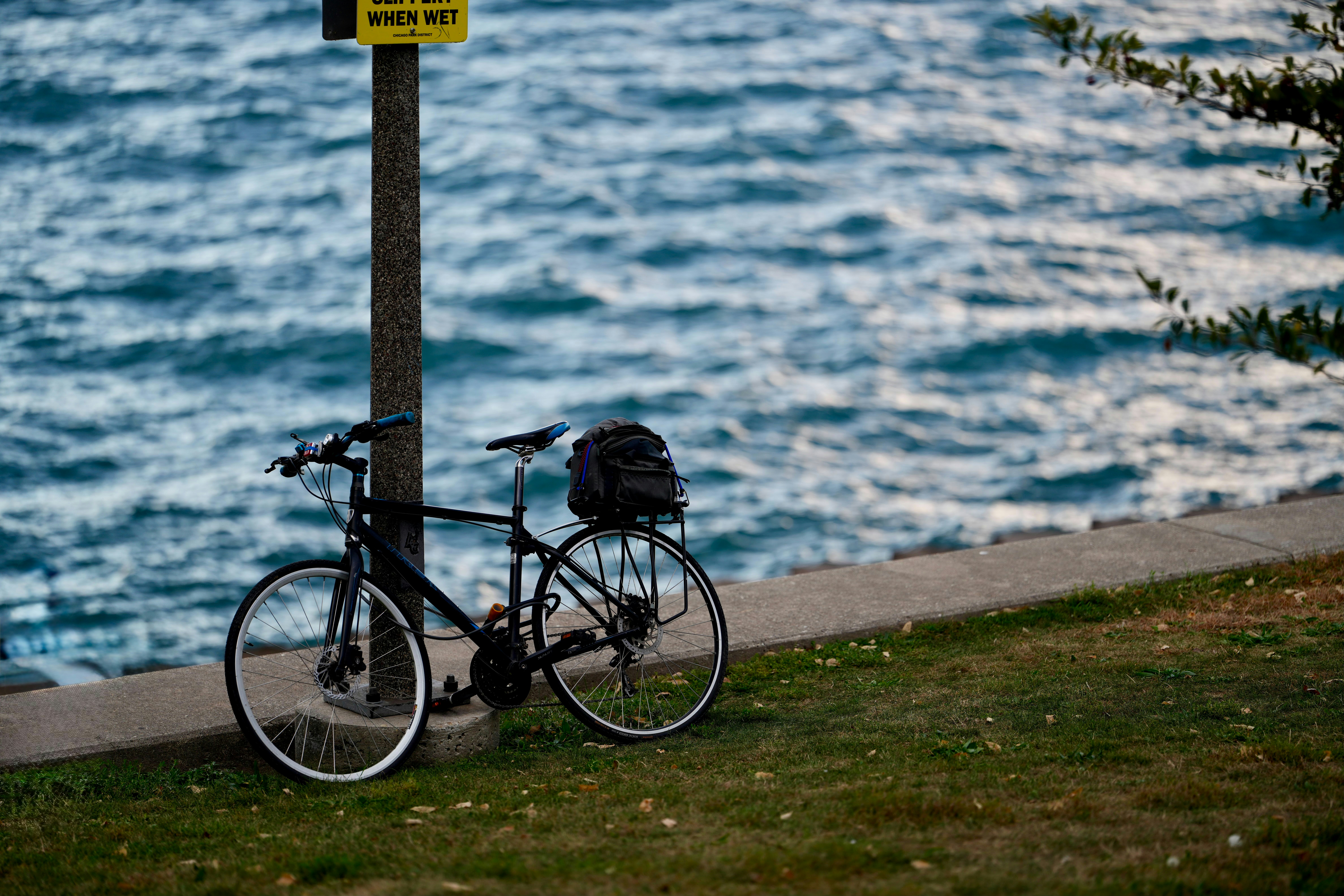 Bicycle parked by the water with a backpack.
