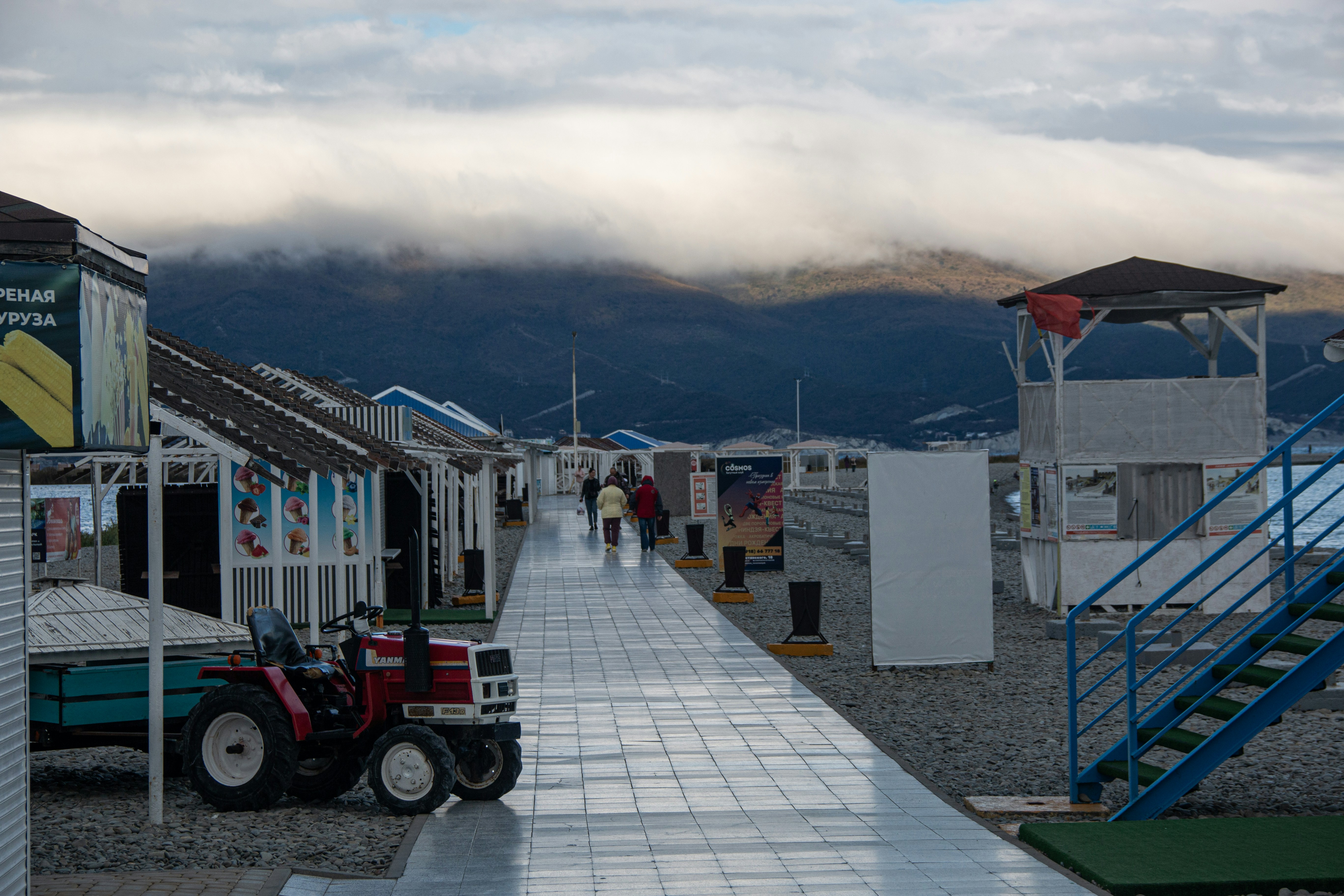 Empty beach stalls with a tractor and mountains.