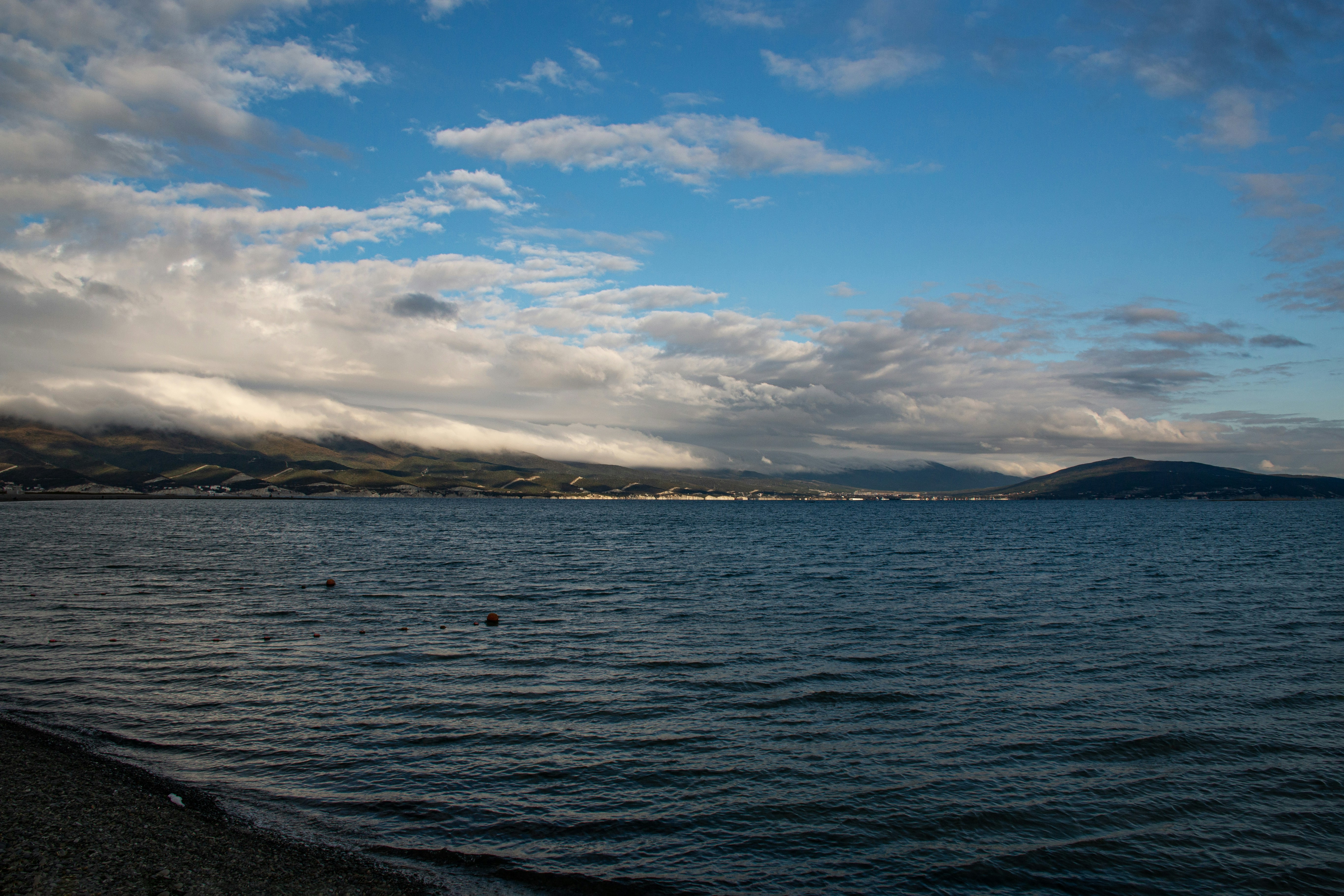 Calm lake with distant mountains and cloudy sky