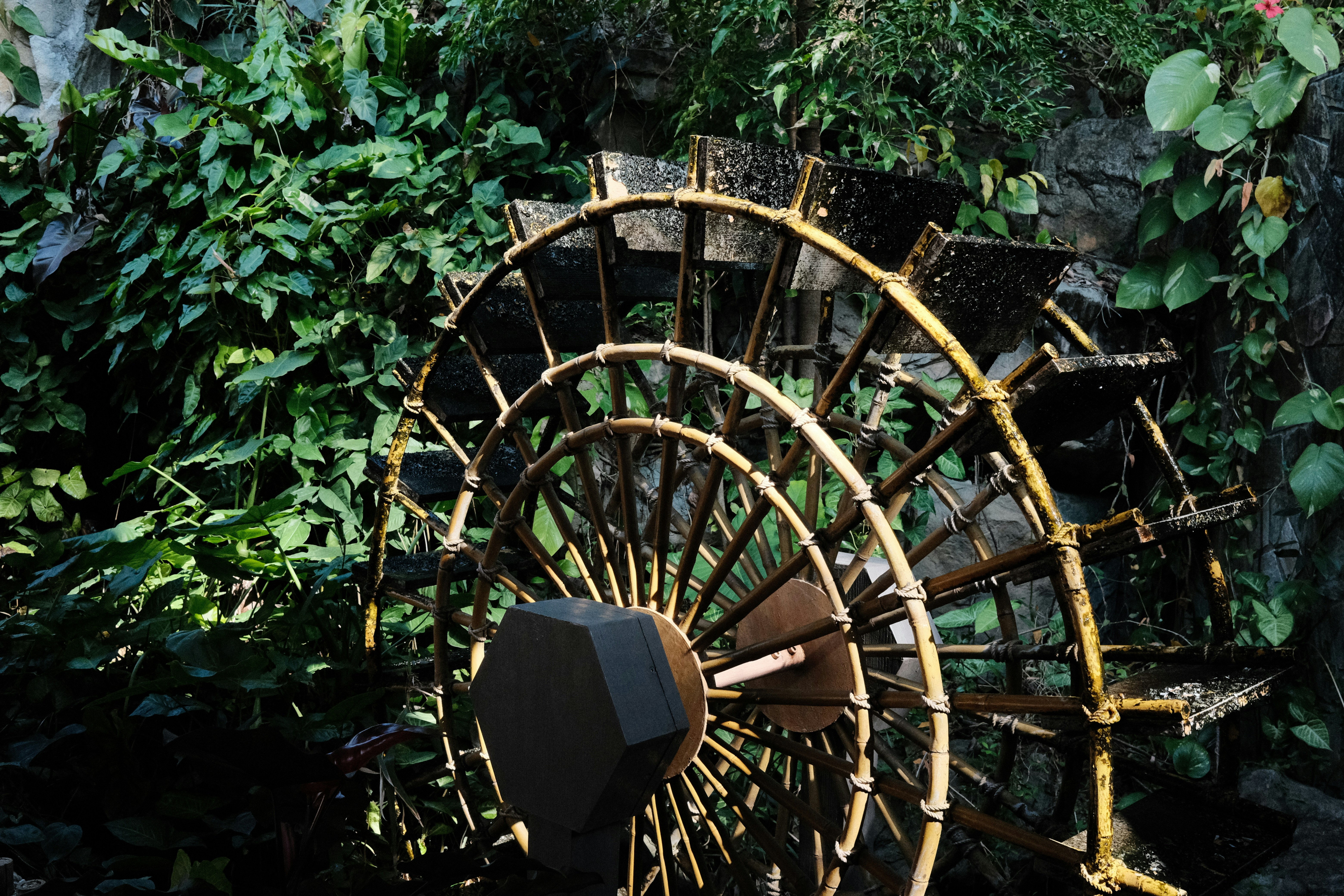 An old water wheel surrounded by lush green foliage.