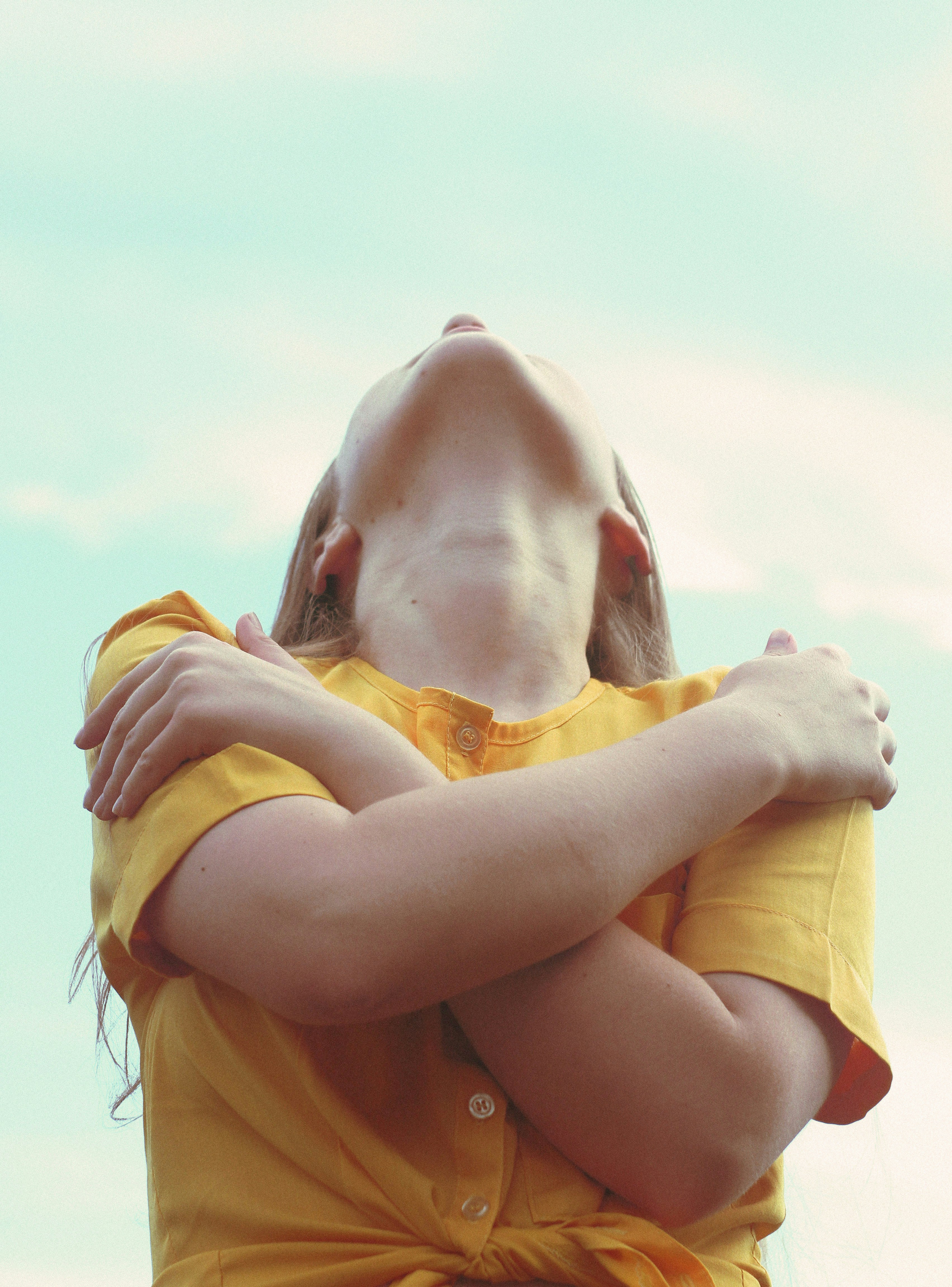 Woman embracing herself against a sky backdrop