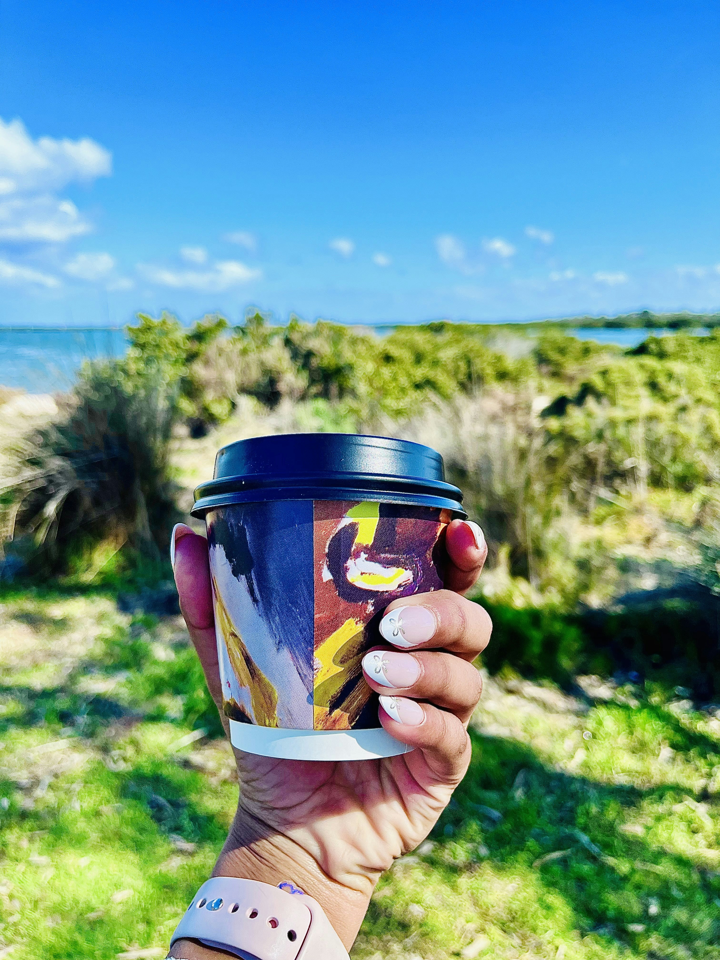A delicious hot chocolate on a cold winters day | Hand holding a coffee cup with a scenic background.