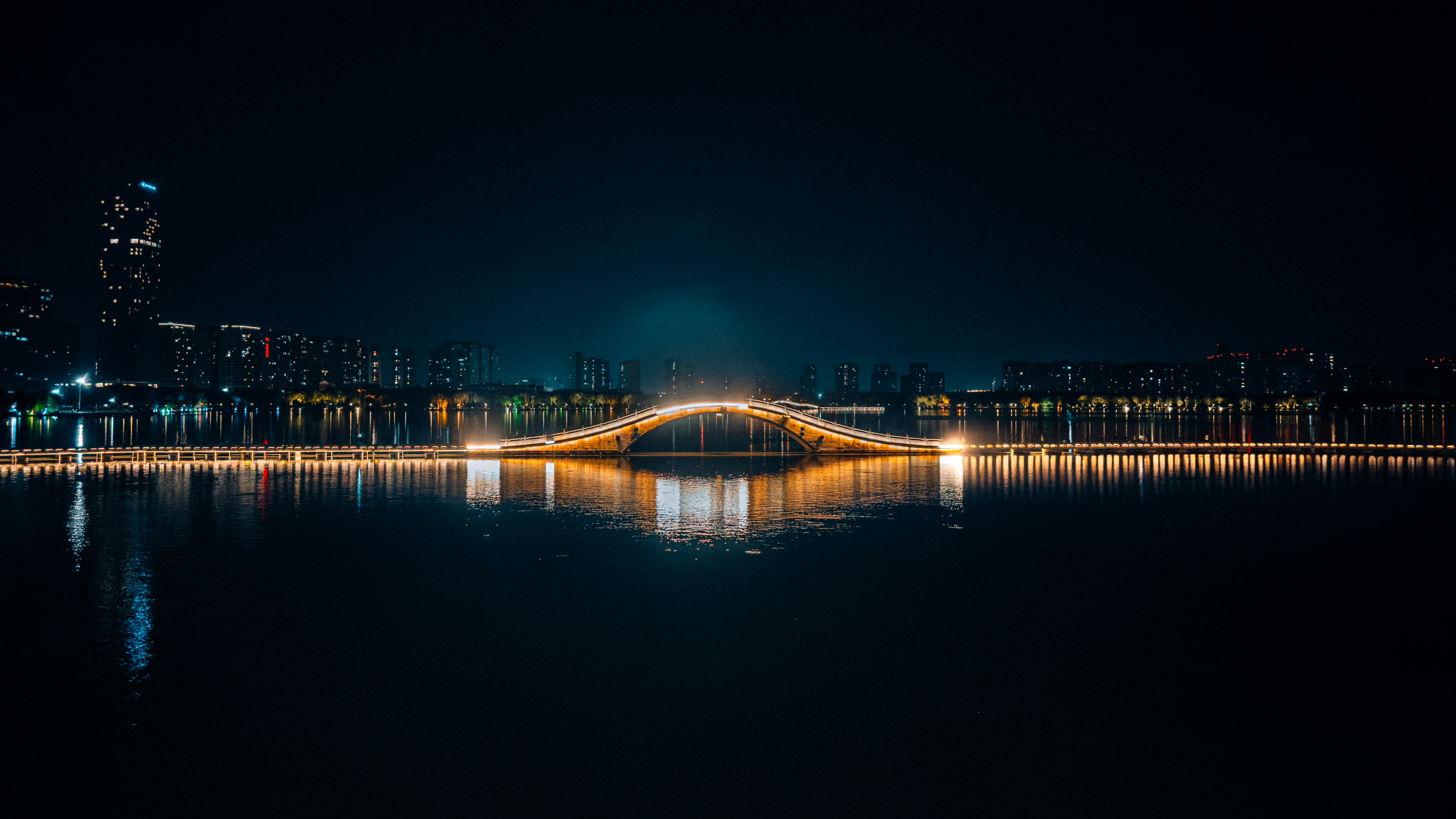 Guazhu Lake, Keqiao. 📸 iPhone 14 Pro Max | Illuminated bridge reflects on calm water at night.