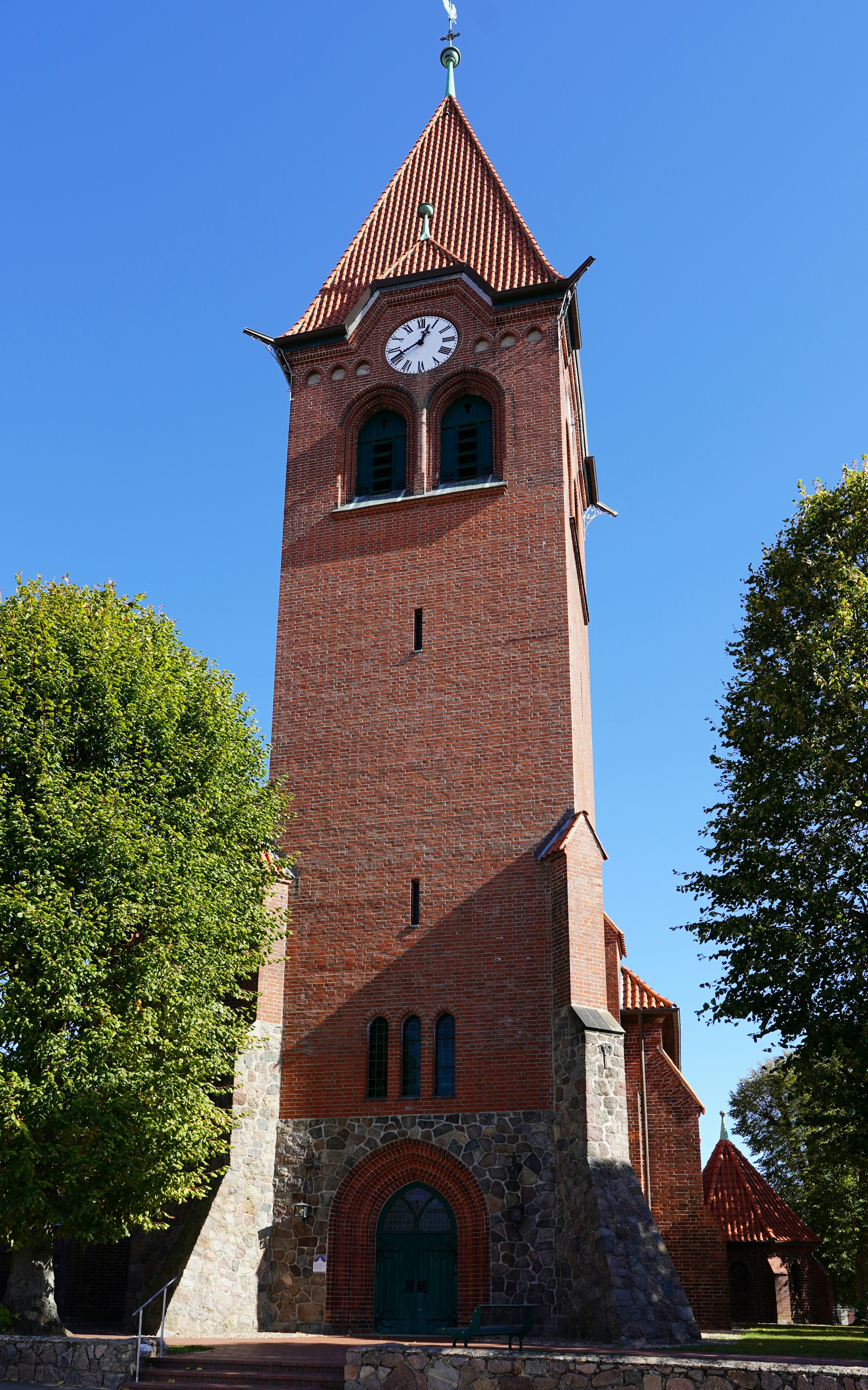 Tall brick church tower with a clock against blue sky