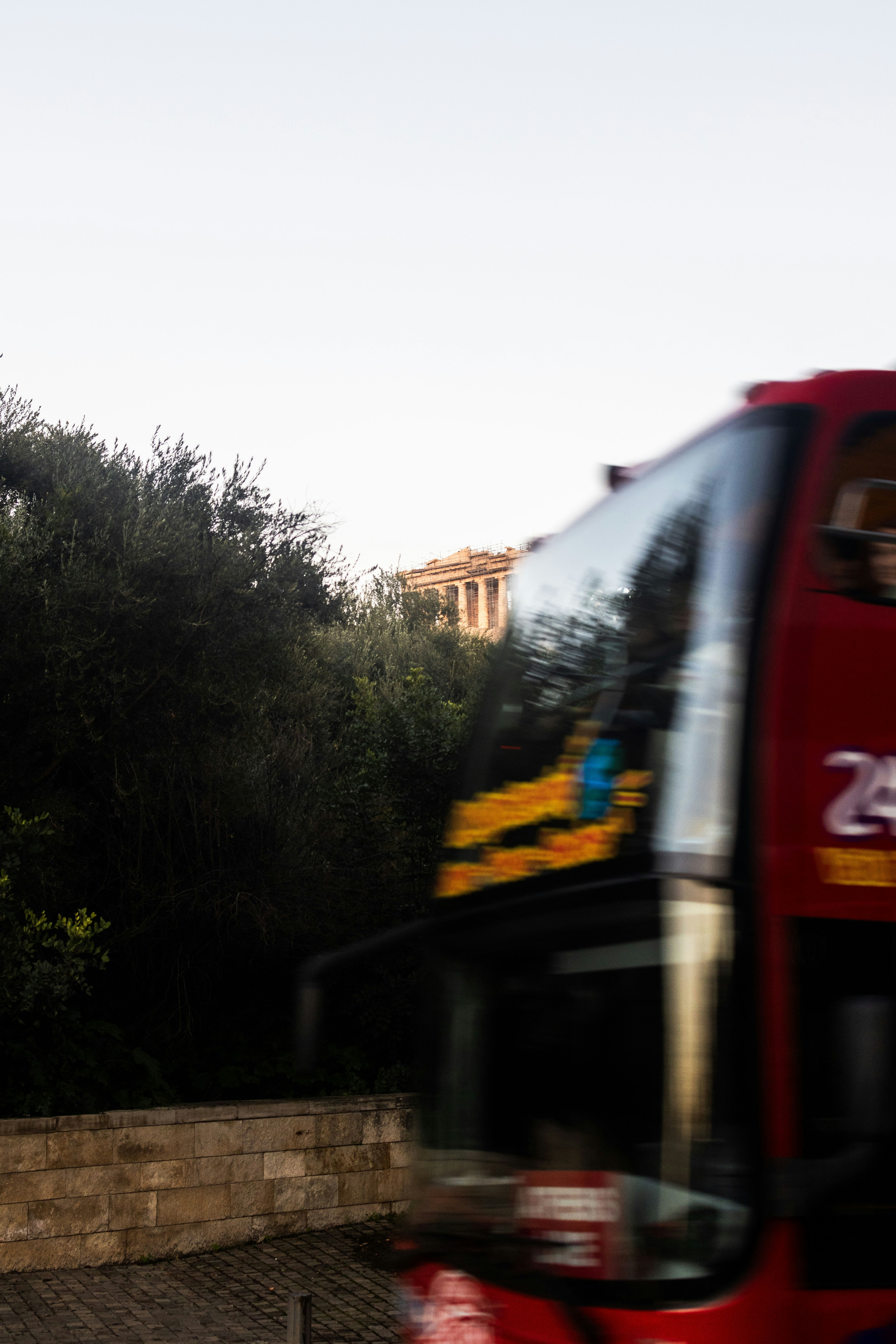 Red double-decker bus blurred in motion with trees.