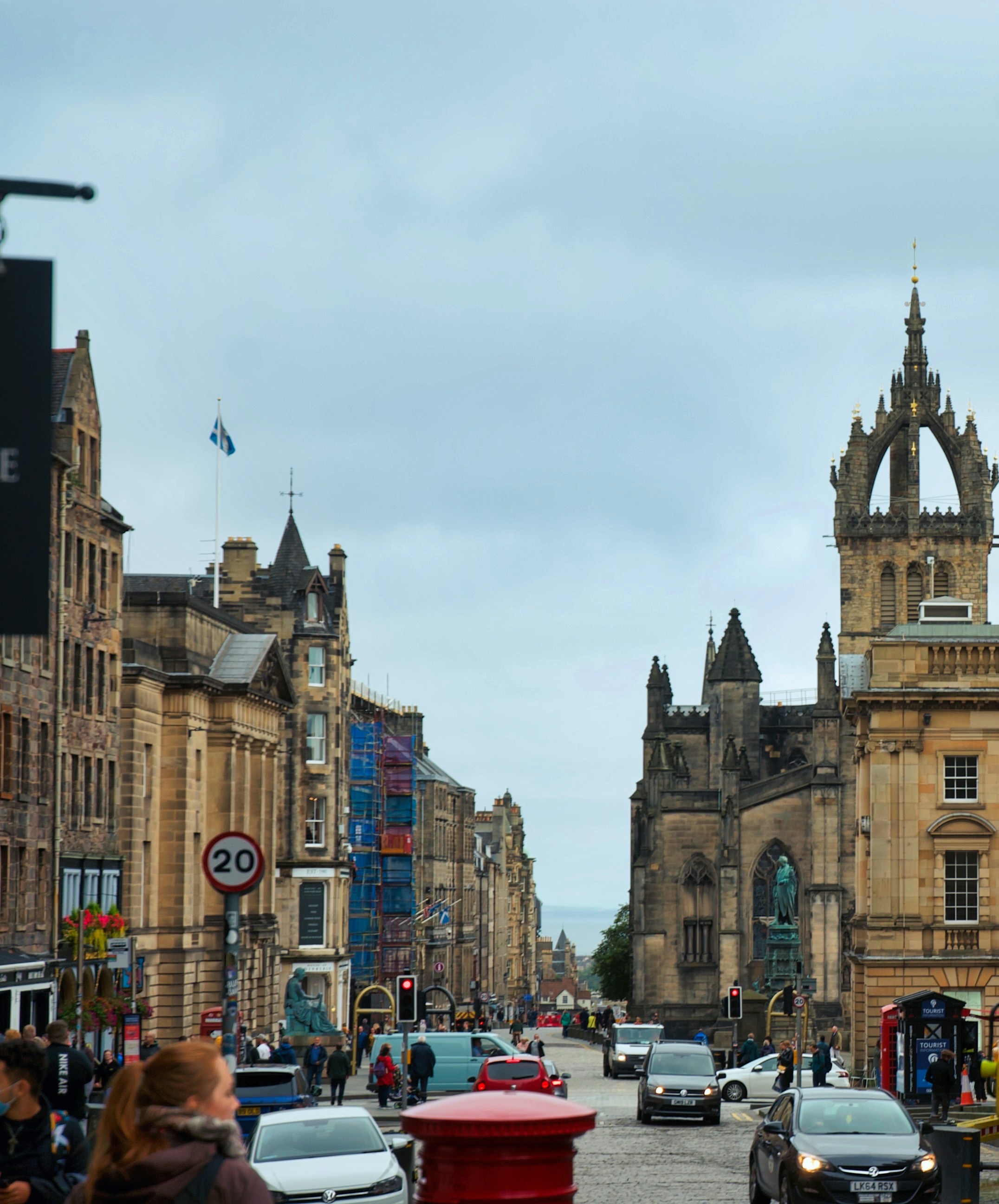 Historic architecture lining a bustling street in Edinburgh, with vehicles and pedestrians adding to the urban scene.