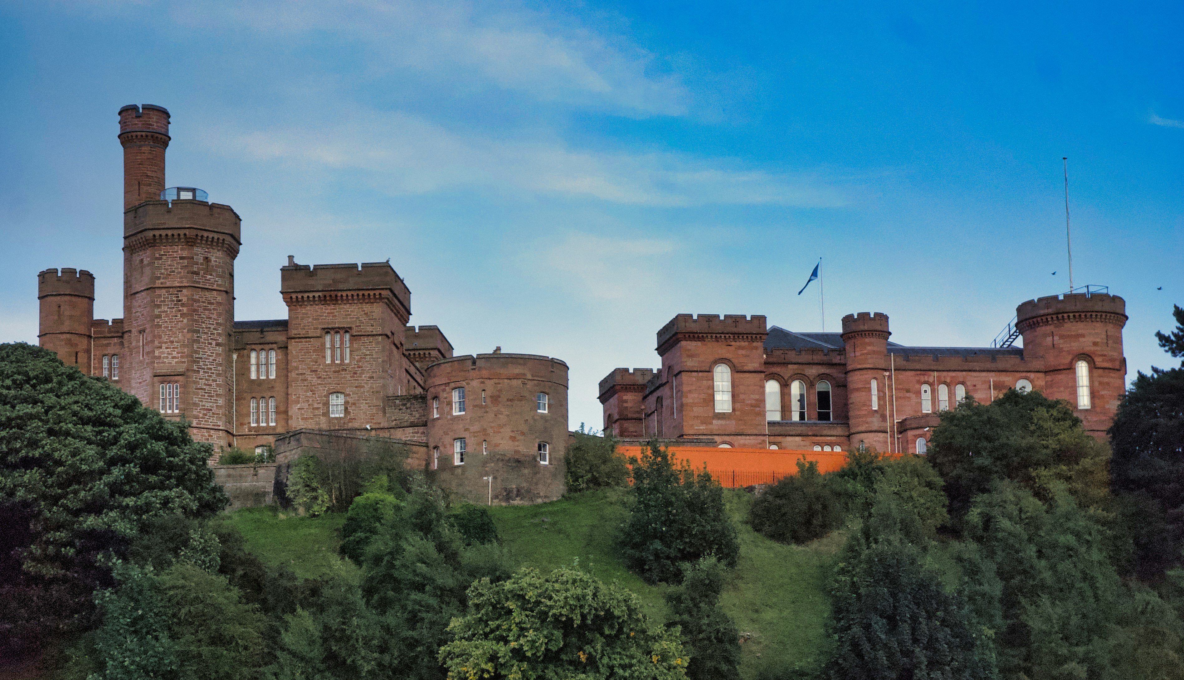 Castle on the Crest: Turrets Framed by a Verdant Hill under a Brisk Blue Sky